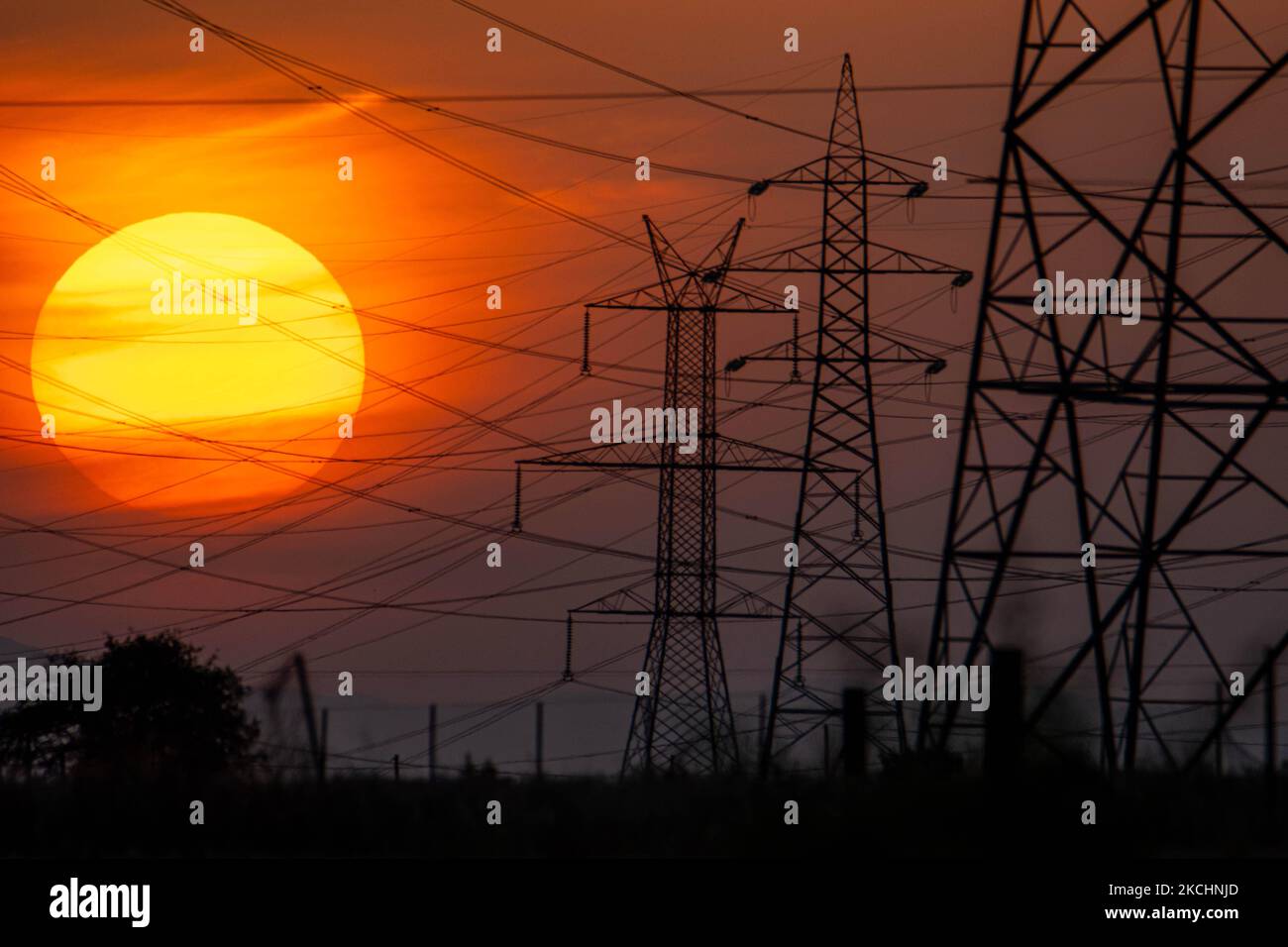 Coucher de soleil d'été en Grèce avec pylônes électriques près de la ville de Thessalonique ...