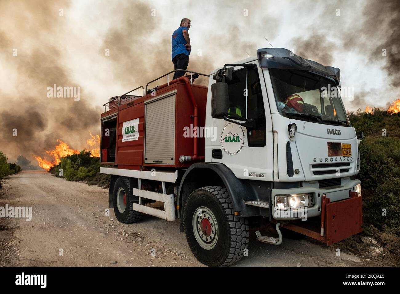 Un pompier au-dessus d'un camion d'incendie se bat avec des flammes ...