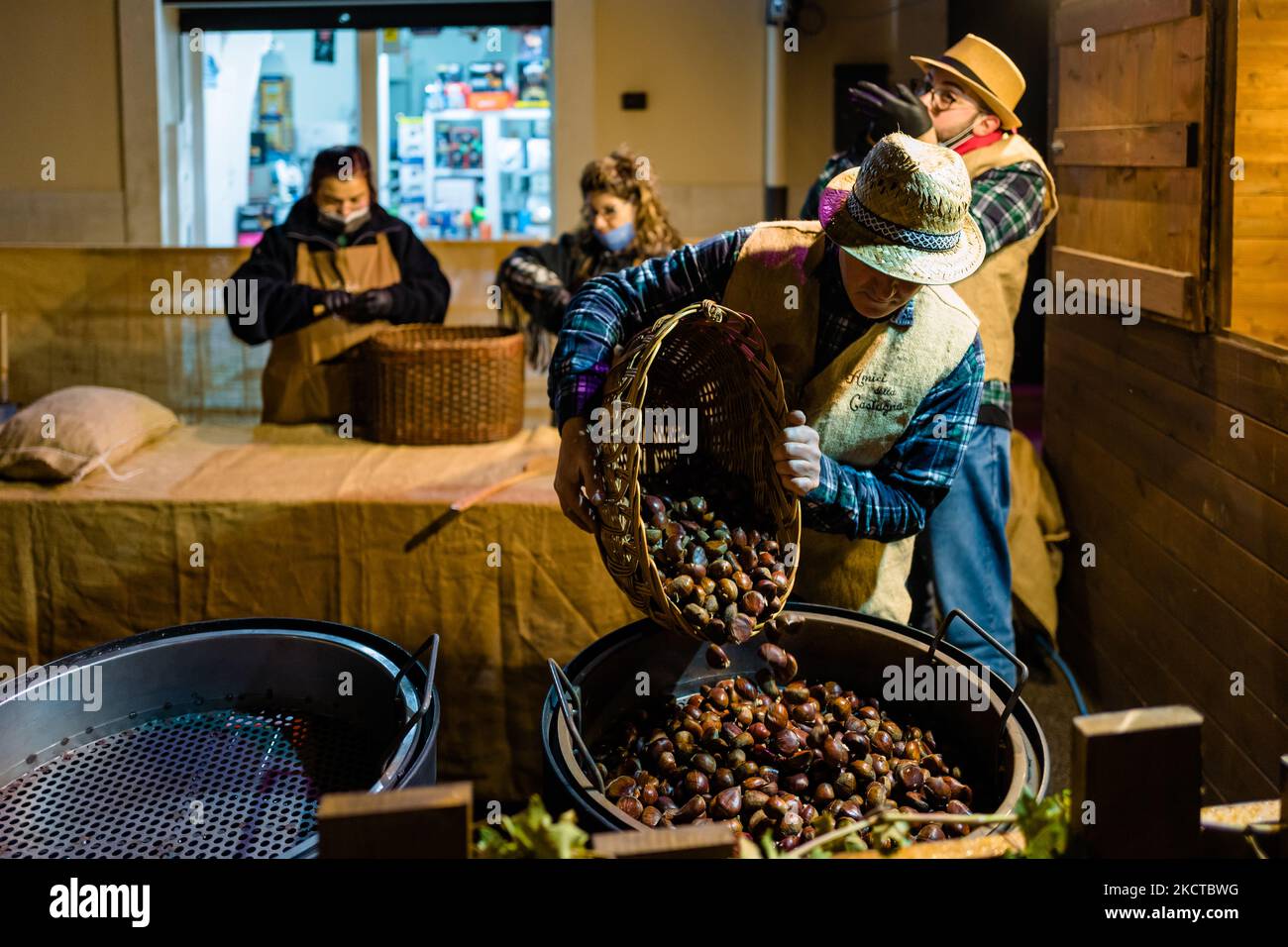 Un monsieur verse des châtaignes dans le pot de caldarroste pendant le ...