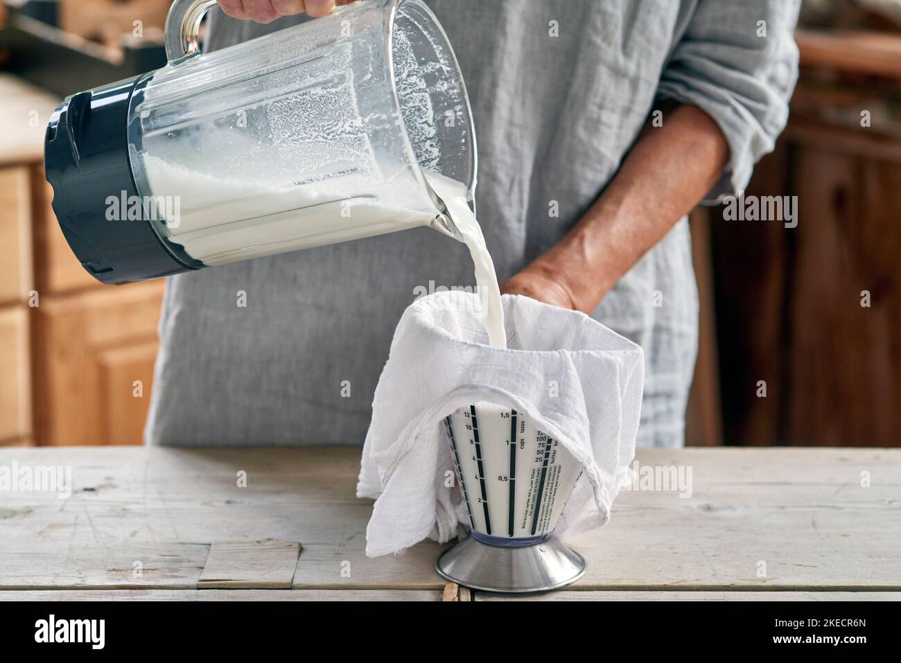 Étapes pour faire du lait d'amande, femme filtre la masse du mélangeur ...