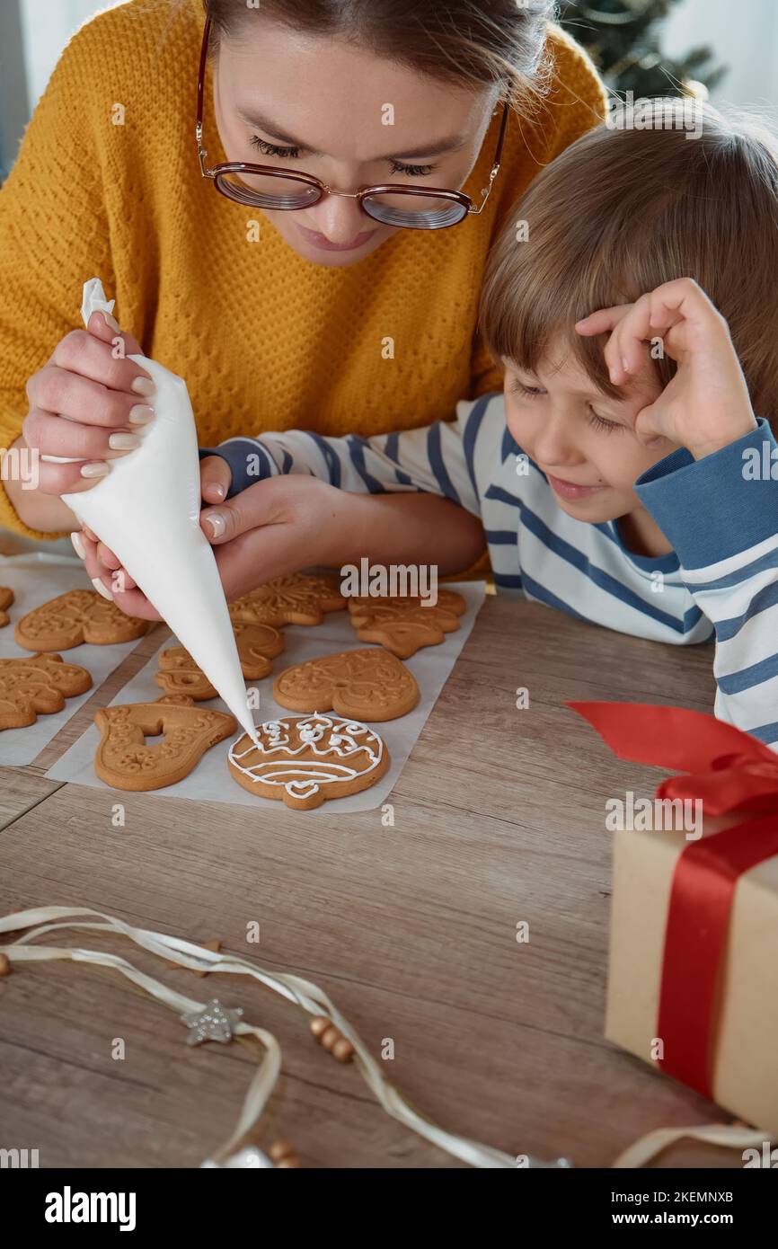 La mère et l'enfant décorent ensemble les biscuits de pain d'épice de ...