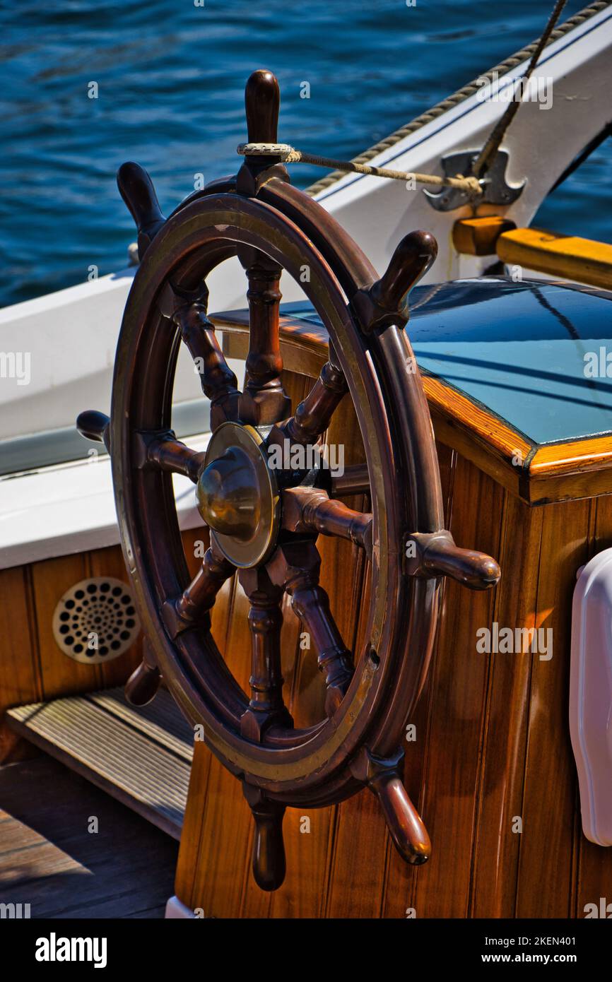 Gros plan vertical d'une roue de gouvernail en bois d'époque sur un vieux bateau sur fond bleu ...
