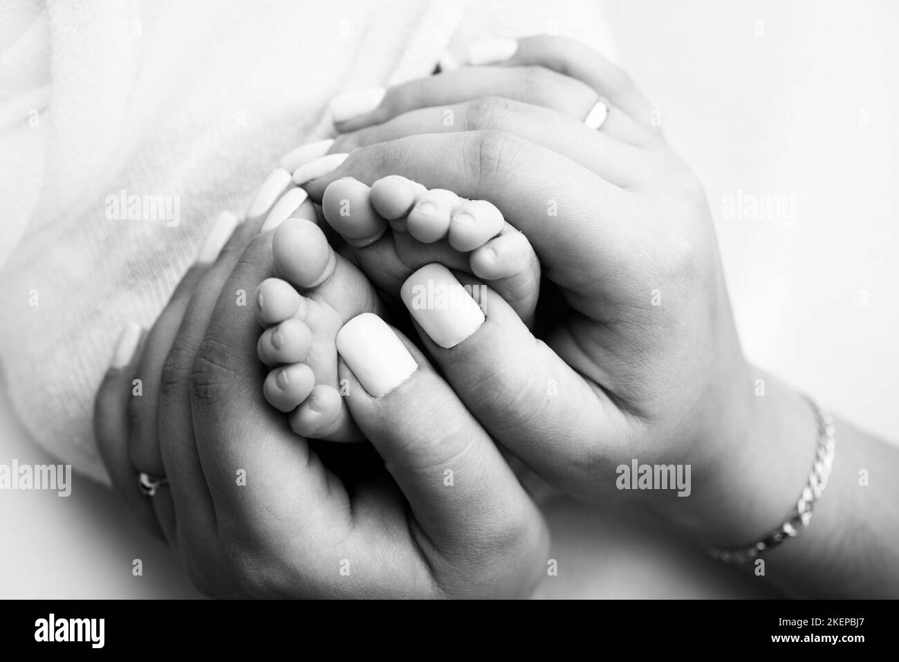 La mère fait un massage sur son pied de bébé. Gros plan des pieds de bébé dans les mains de la ...