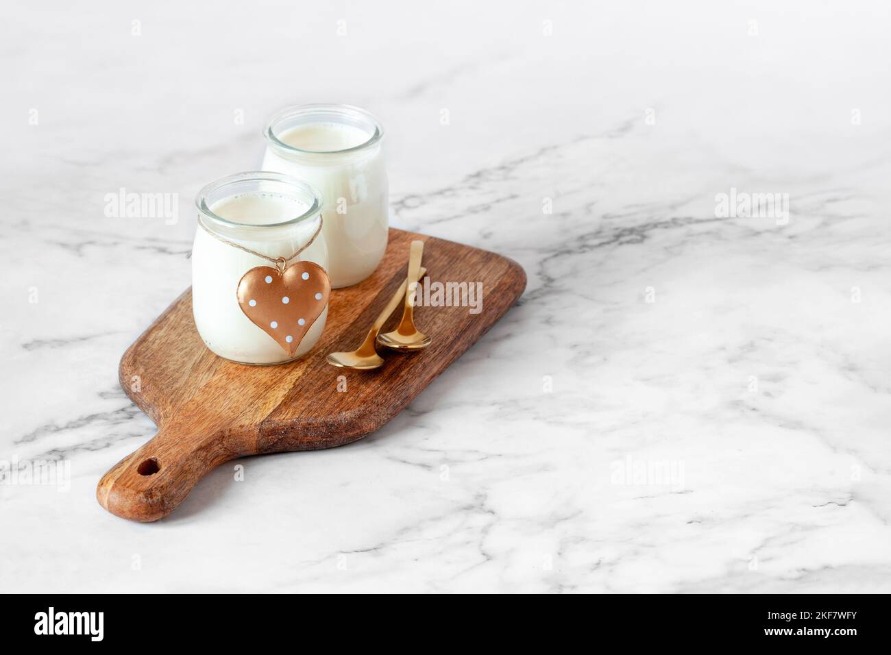 deux pots en verre de yaourt sur le petit plan de découpe en bois ...