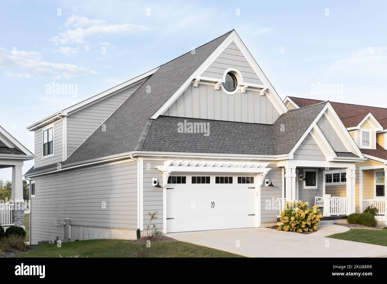 Une grande maison grise avec parement vertical et vinyle, auvent de ...