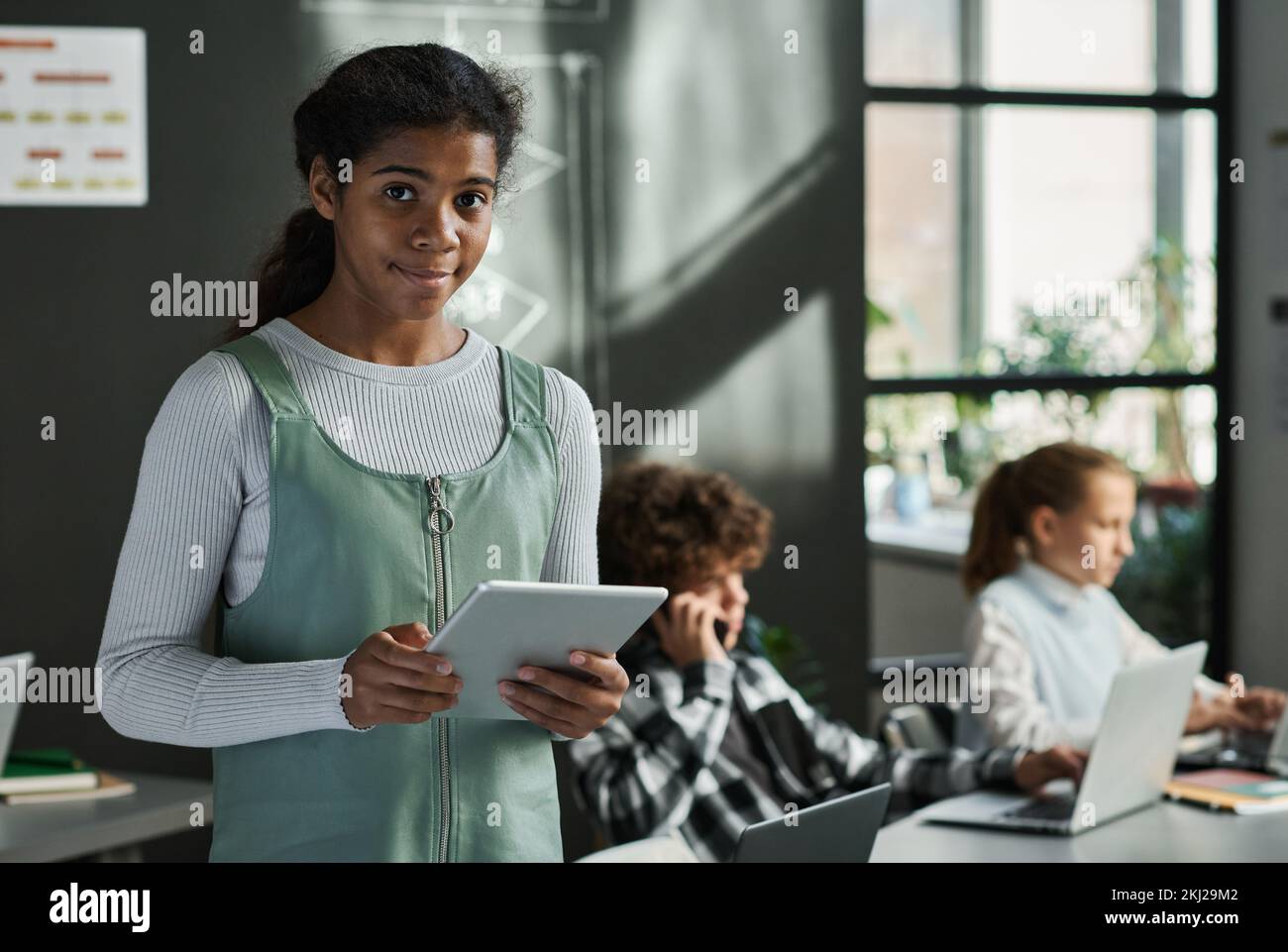 Portrait d'une écolière afro-américaine avec tablette pc, regardant un ... Portrait d'une écolière afro-américaine avec tablette pc, regardant un ...