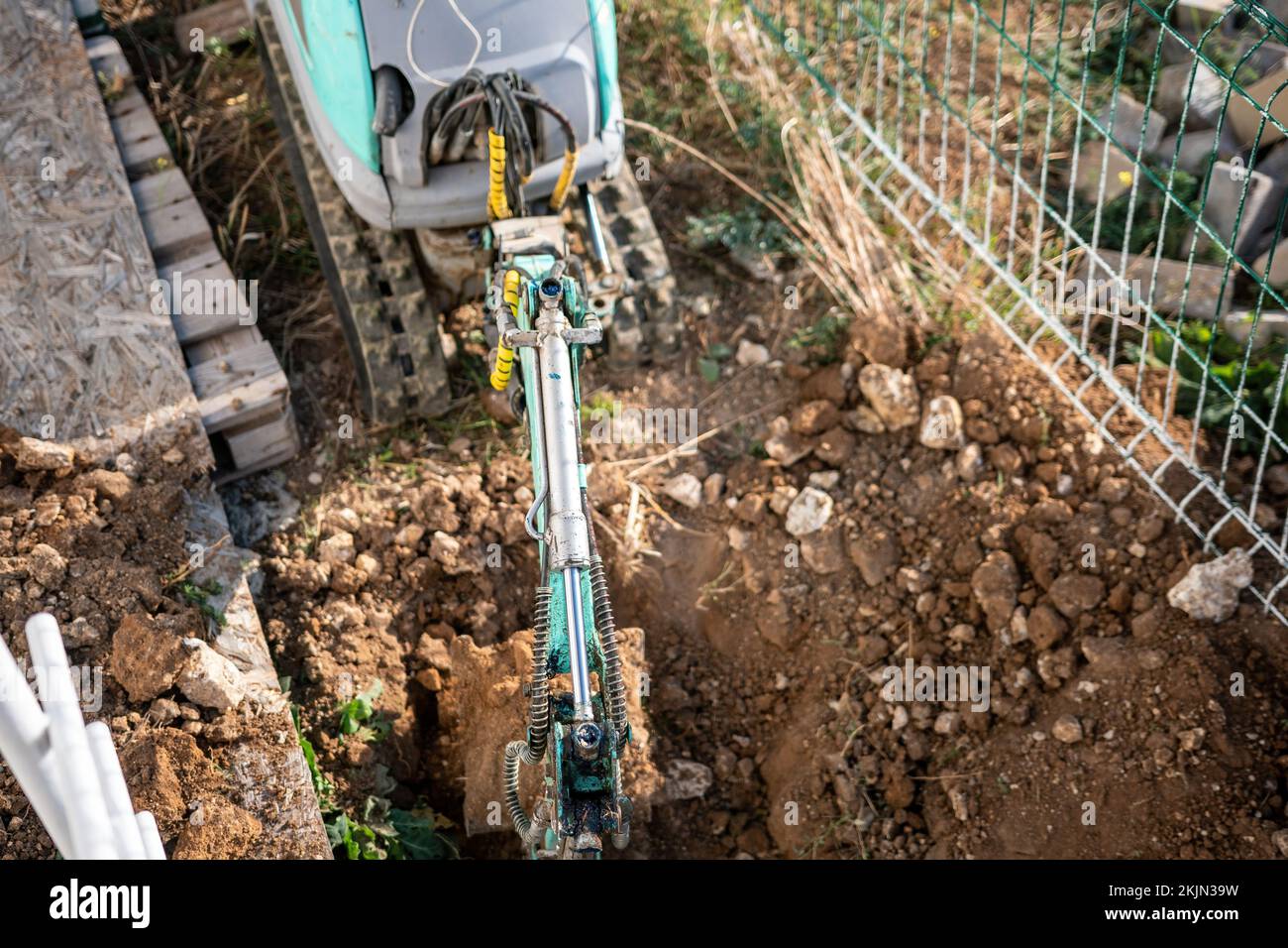 Une minipelle creuse une tranchée pour poser les tuyaux. Gros plan d ...