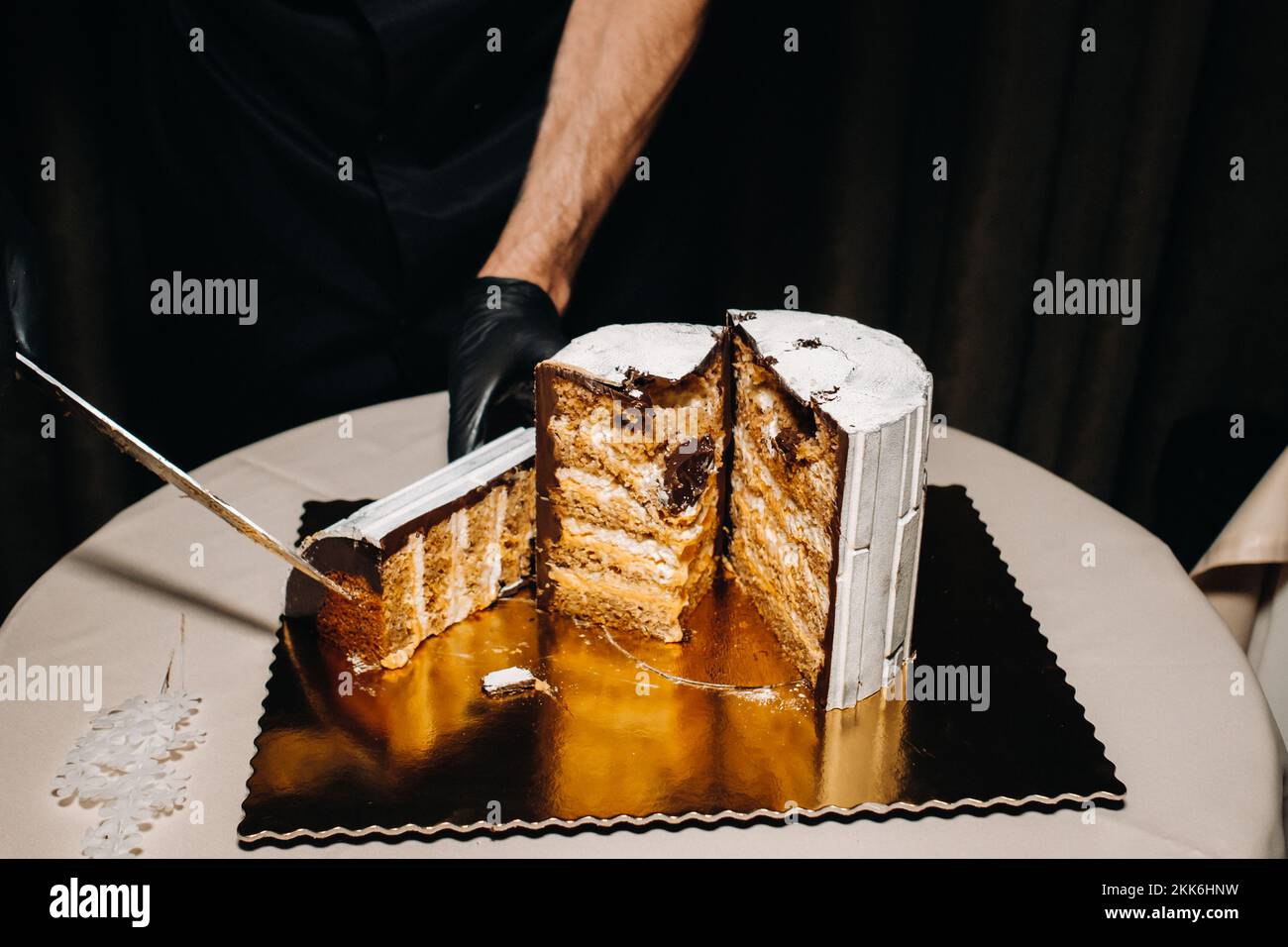 Des gâteaux incroyables. Un chef aux gloved noirs coupe un gâteau de ...