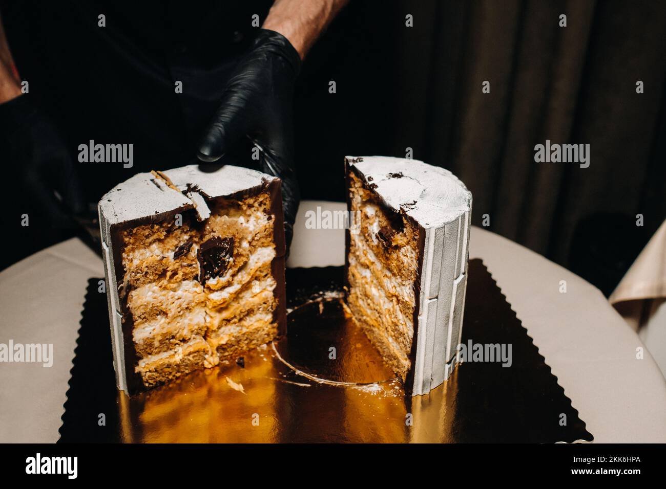 Des gâteaux incroyables. Un chef aux gloved noirs coupe un gâteau de ...