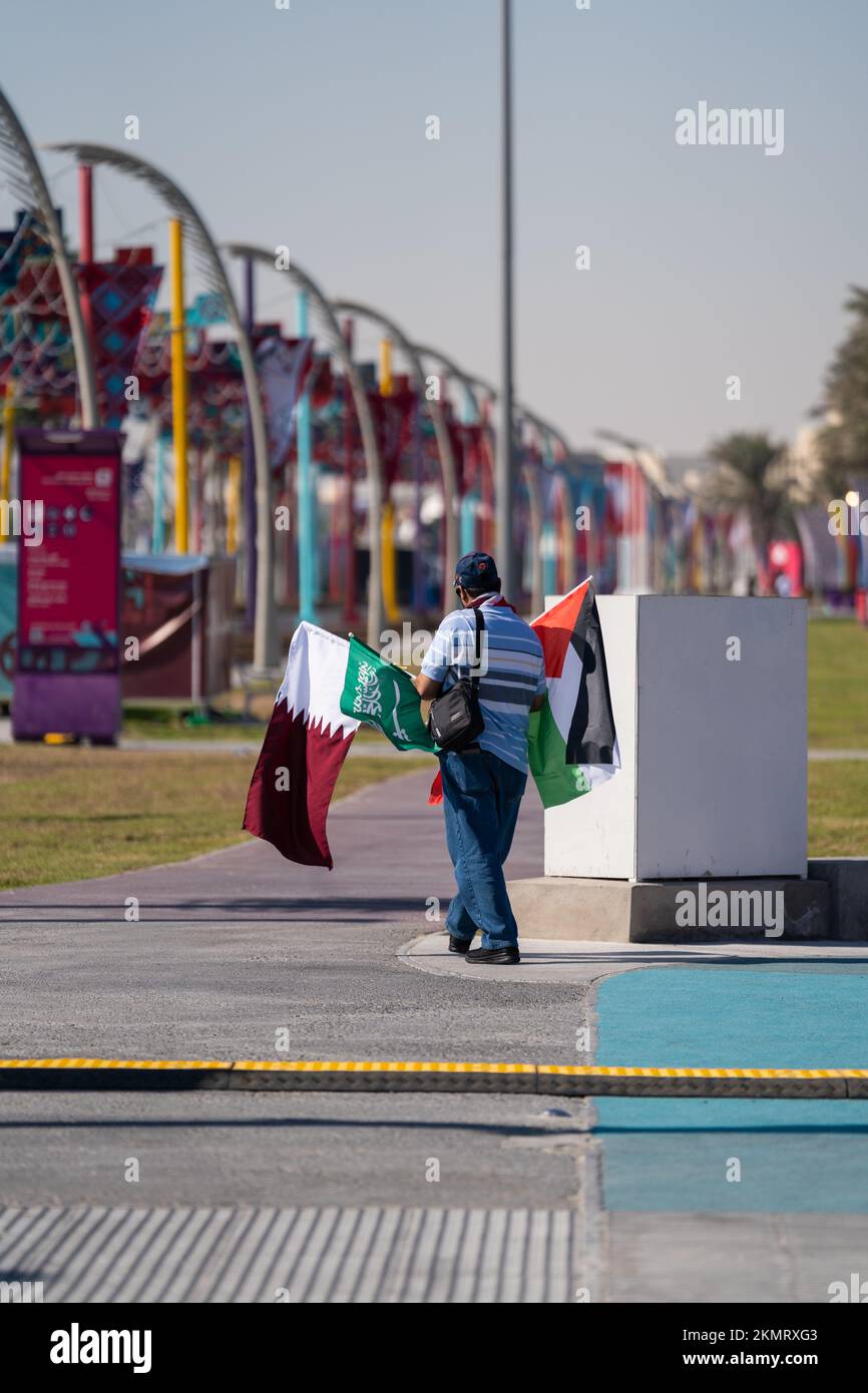 Un homme portant des drapeaux tout en marchant dans la corniche de Doha pendant la coupe du ...