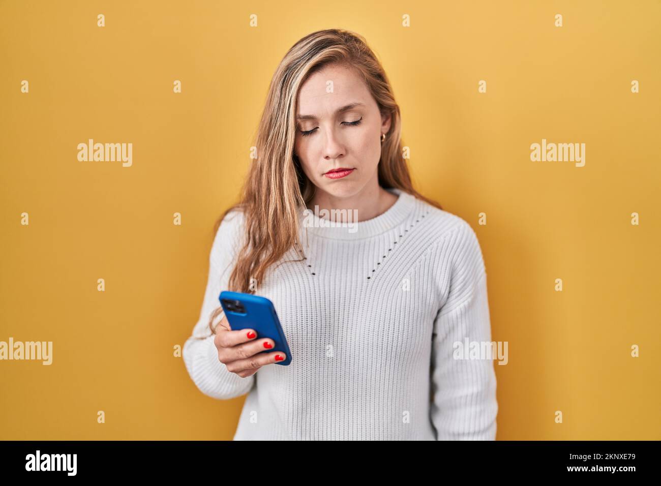 Jeune femme blonde utilisant un smartphone tapant un message qui a l ...