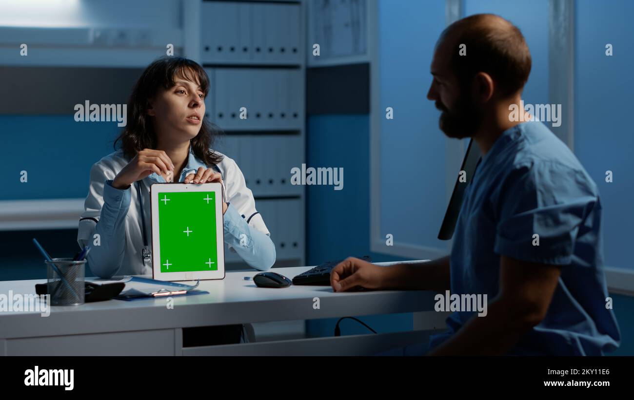 Le médecin tenant un ordinateur tablette pointant vers le modèle de clé à écran vert chroma tout ...