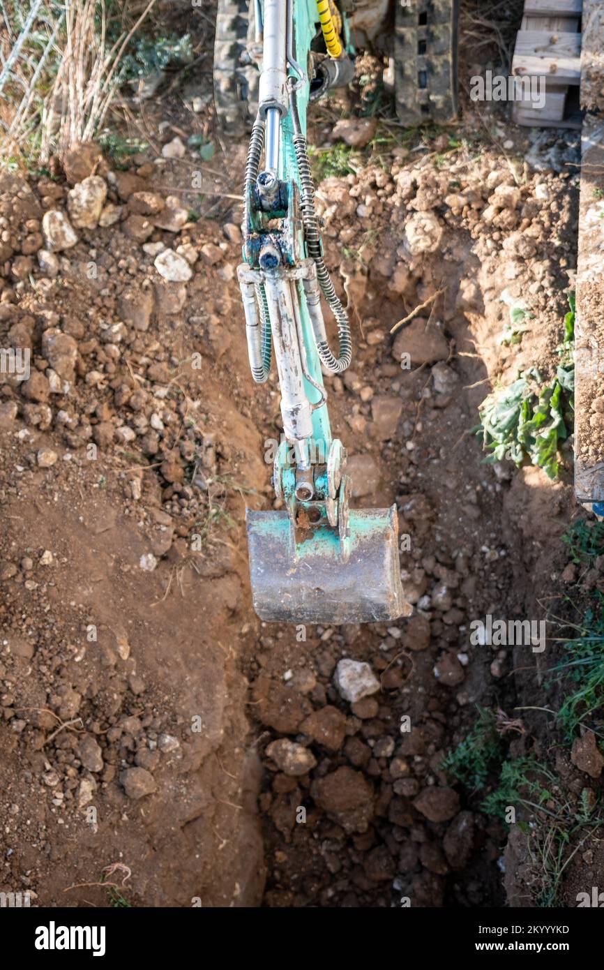 Une minipelle creuse une tranchée pour poser les tuyaux. Gros plan d ...