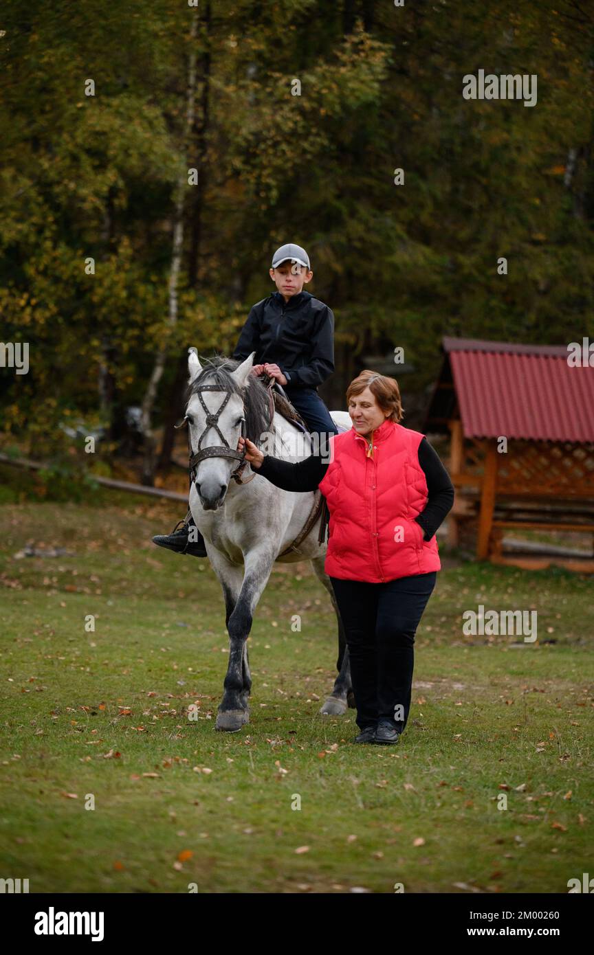 Grand-mère et petit-fils dans le parc, le garçon est assis sur un ...