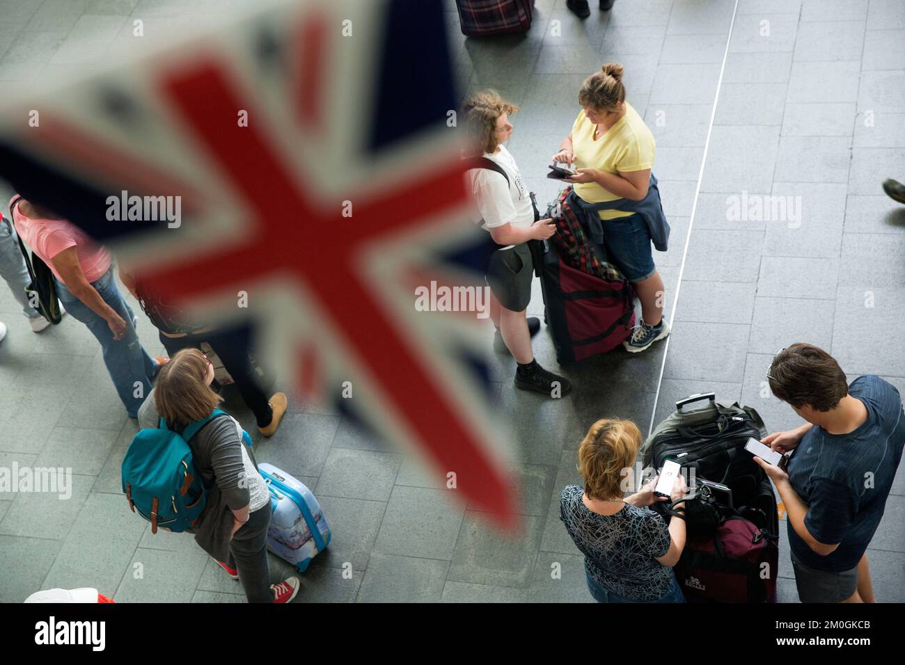 Les voyageurs munis de valises sont vus derrière un Union Jack qui fait ...