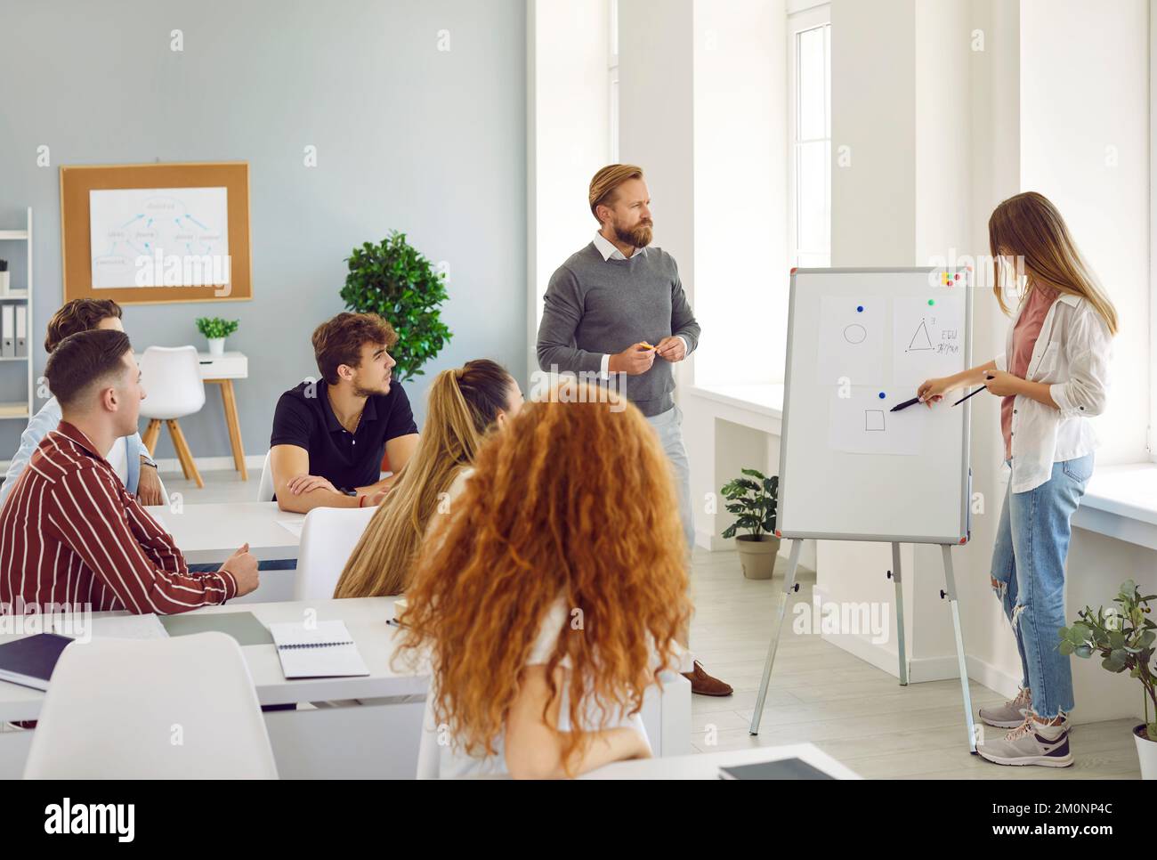 Une jeune fille étudiante de l'université écrit sur un tableau blanc en ...