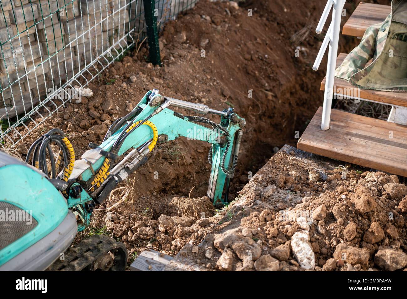 Une minipelle creuse une tranchée pour poser les tuyaux. Gros plan d ...