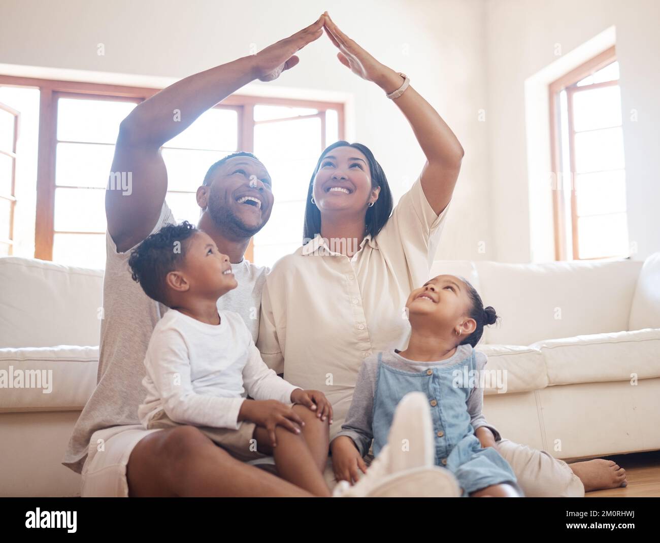 Parents élégants de race mixte avec deux enfants assis sur le sol ...