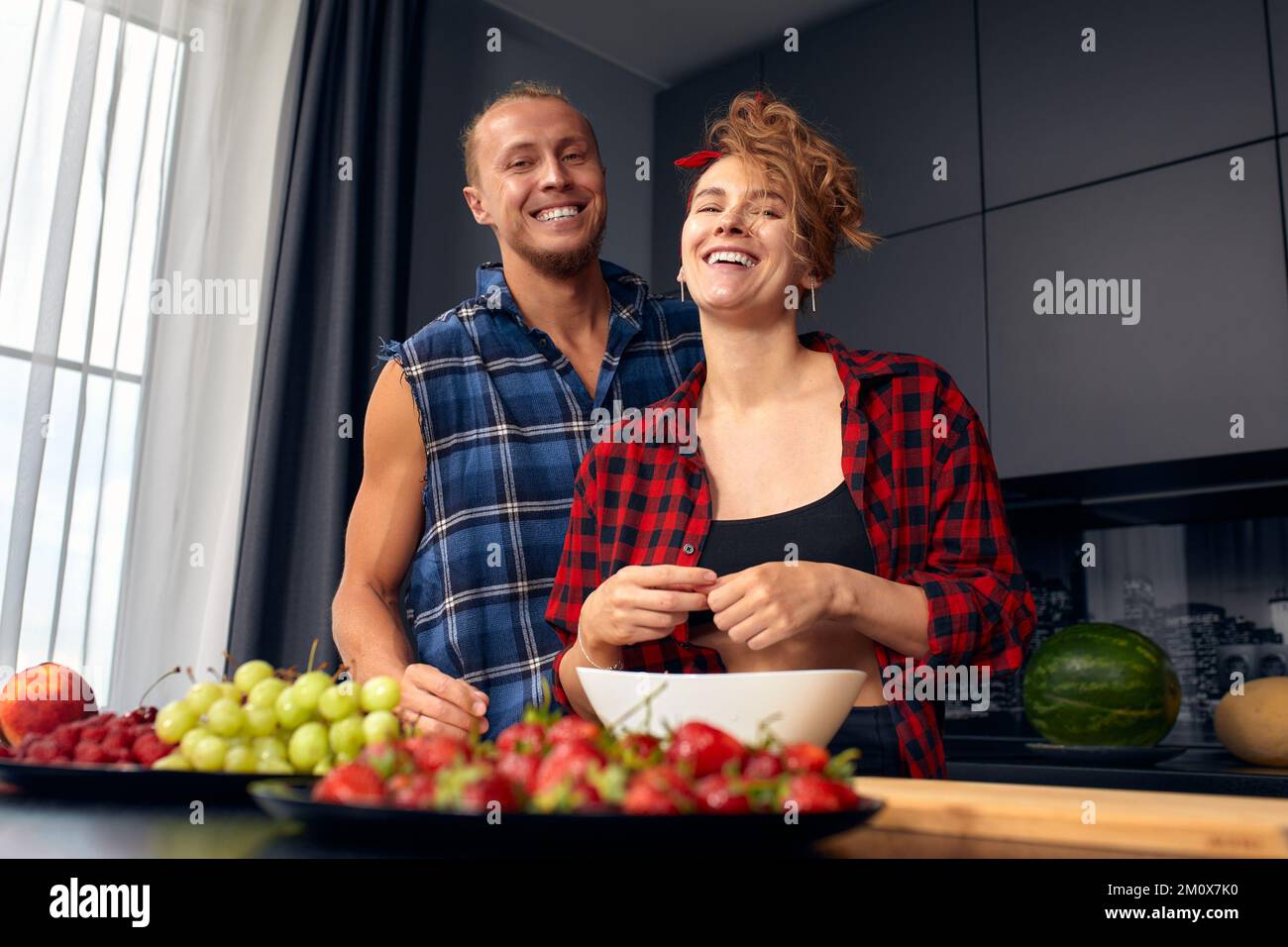 Heureux couple debout dans la cuisine à la maison préparant ensemble ...