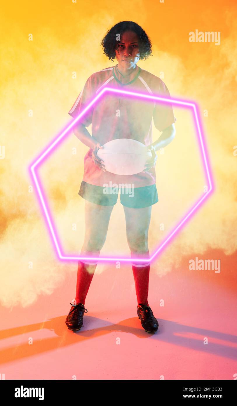 Joueuse de rugby biraciale confiante avec balle debout au milieu de la ...