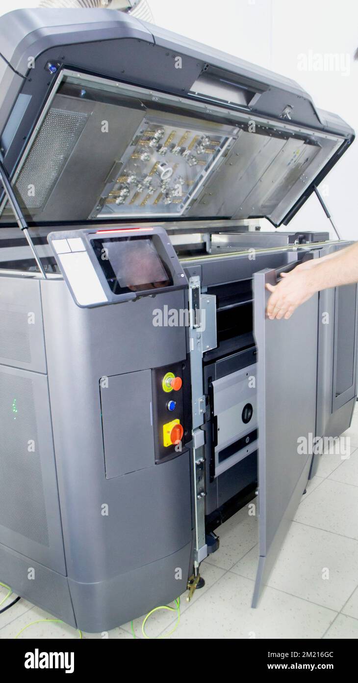 Un travailleur et une grande imprimante industrielle en poudre 3D dans ...