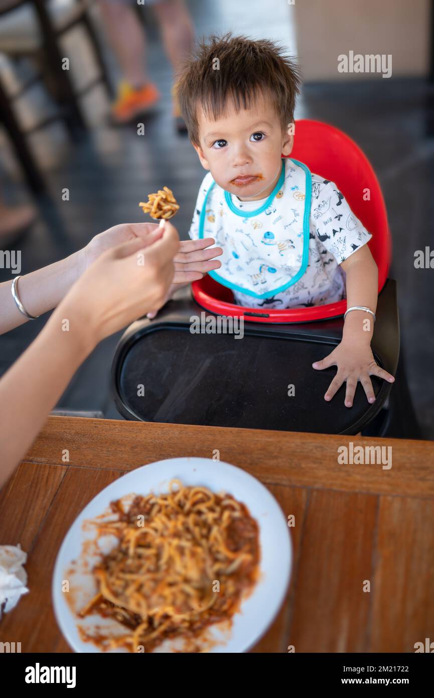 Enfant nourri au restaurant par sa mère. Beau petit garçon multiracial ...
