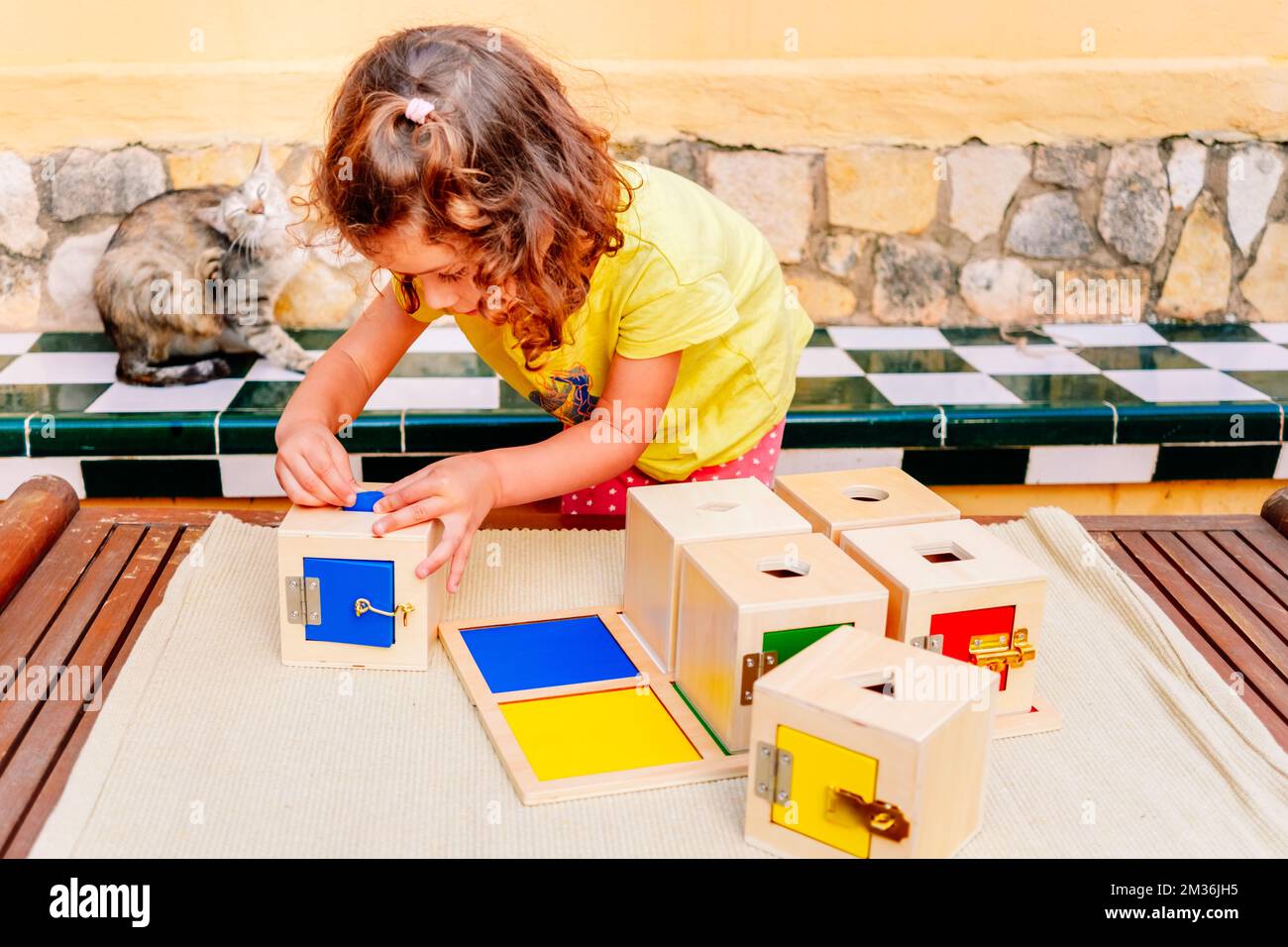 Une fille manipule le matériel sensoriel montessori, des boîtes en bois ...