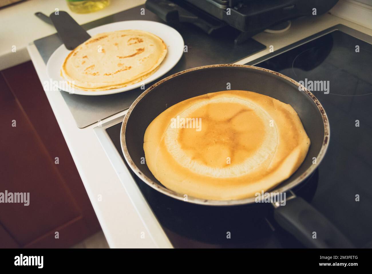 Faire frire des crêpes dans une poêle sur une table de cuisson à ...