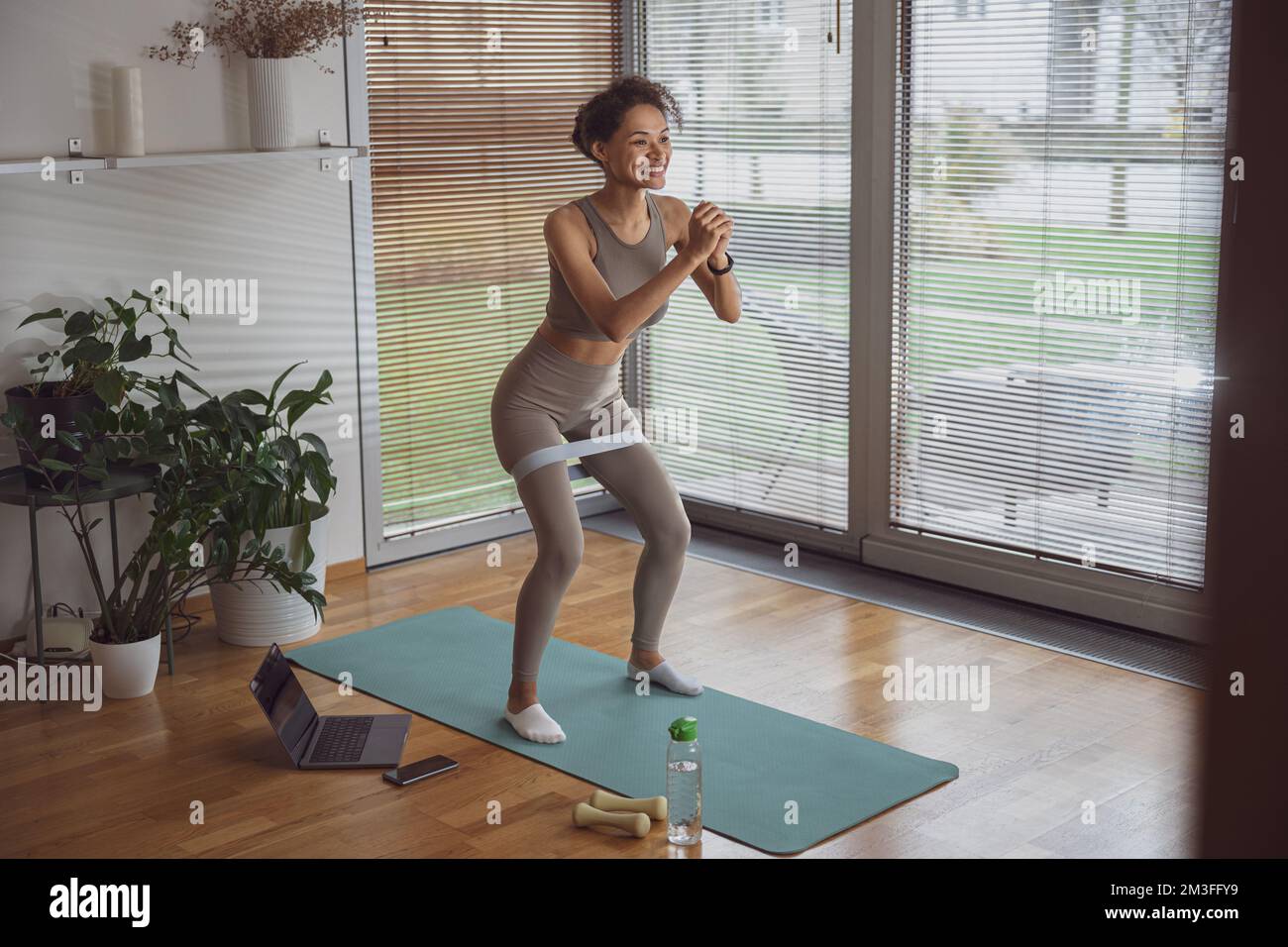 Femme mince faisant des exercices pour les jambes avec bande élastique ...