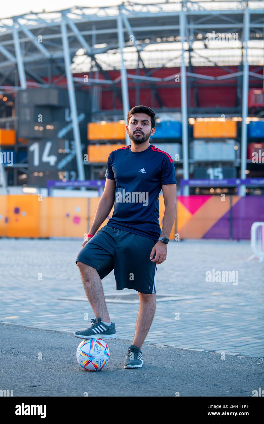 Jeune homme tenant FIFA Qatar football Al Rihla. face au 974 Stadium ...