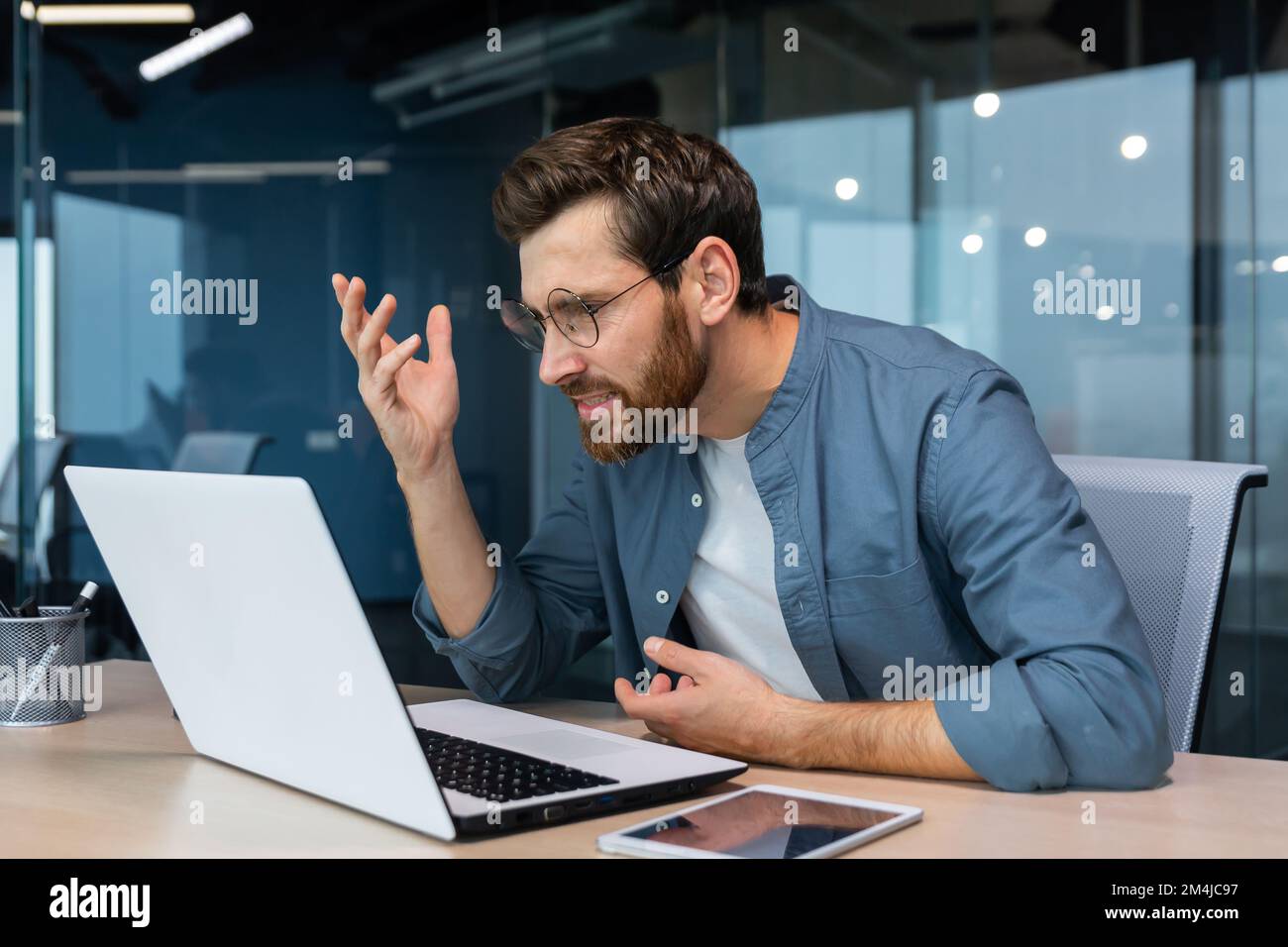Un homme d'affaires mécontent et en colère regardant l'écran d'un ordinateur portable, un homme ...