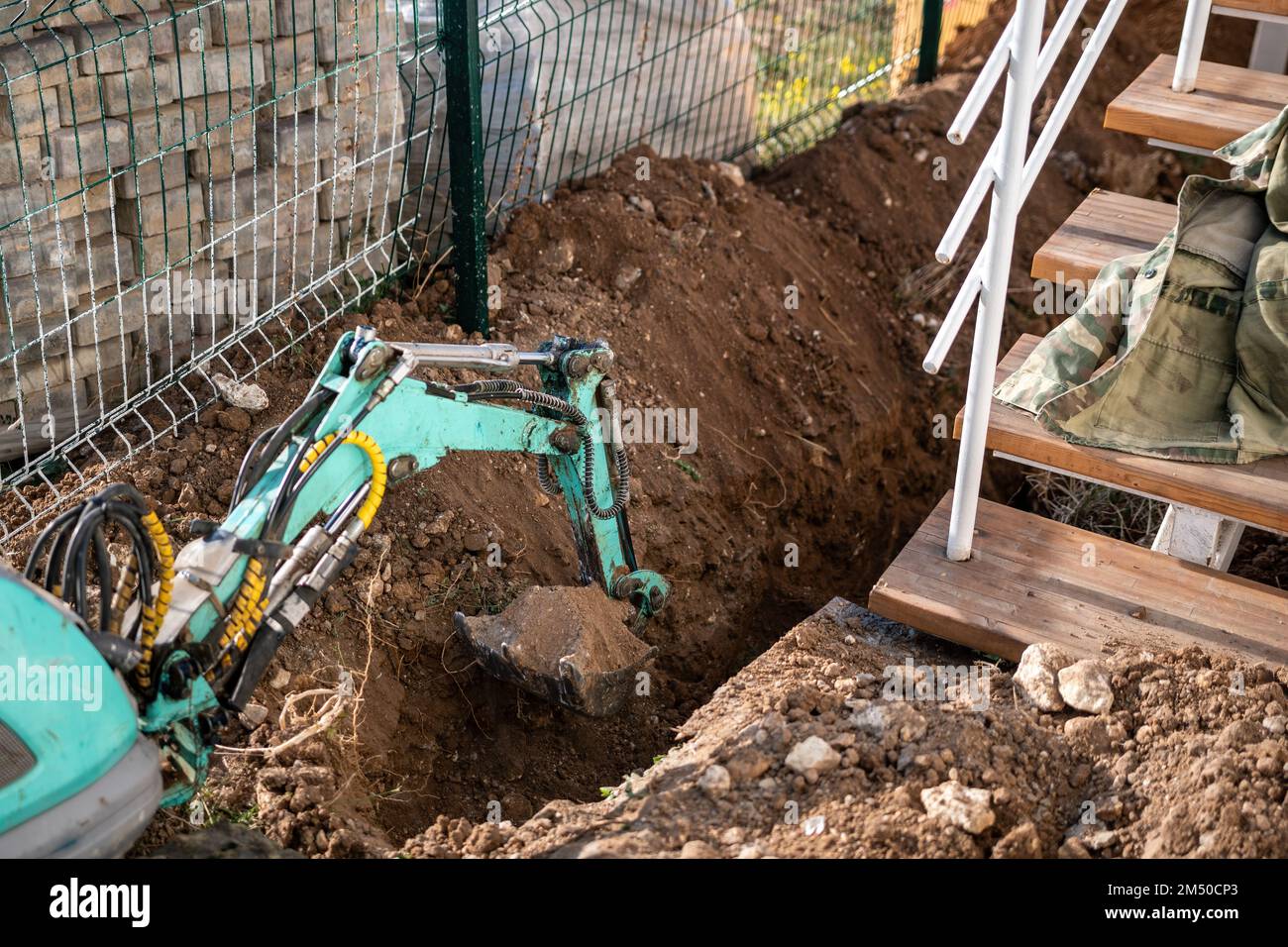 Une minipelle creuse une tranchée pour poser les tuyaux. Gros plan d ...
