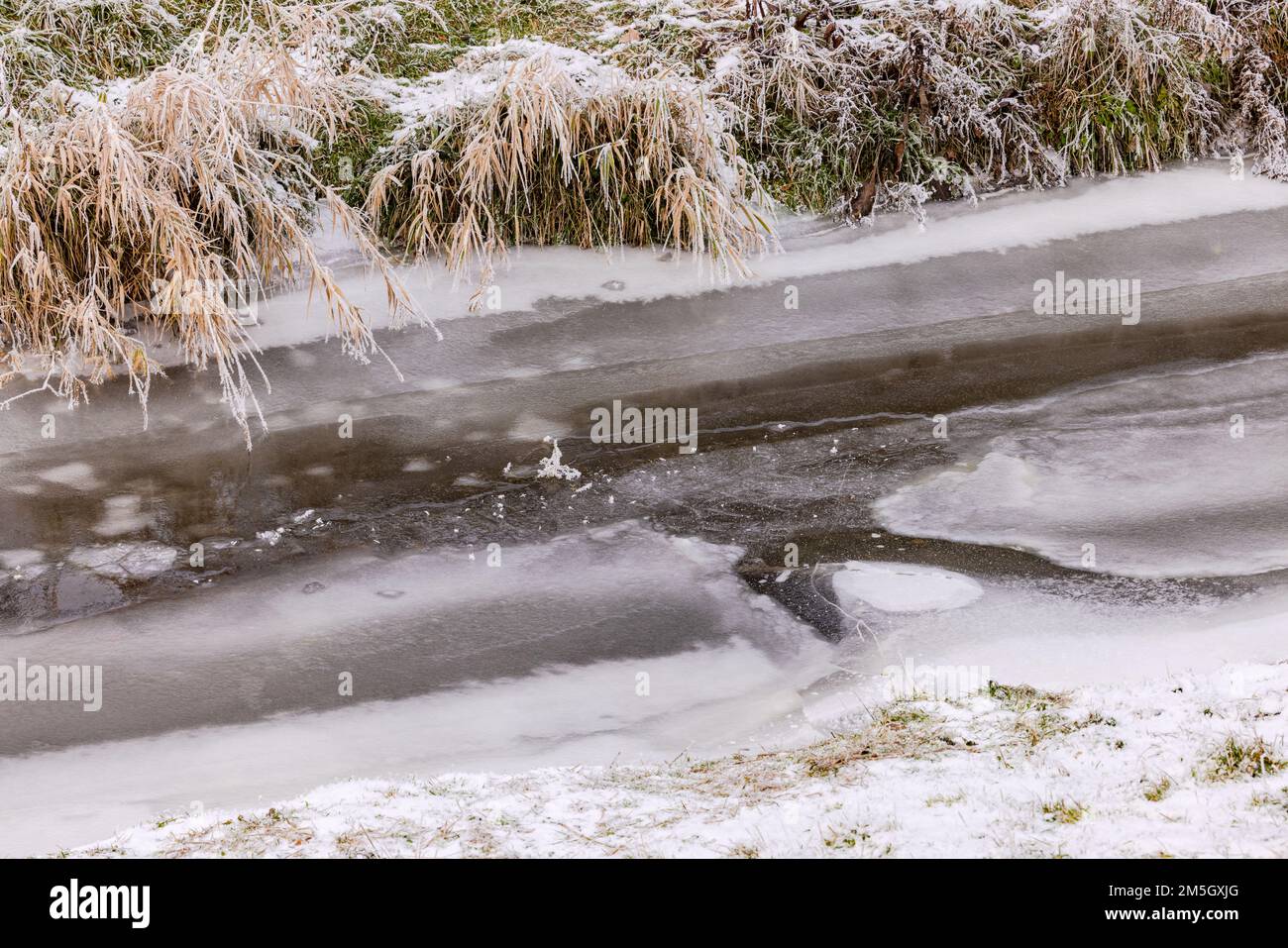 Un ruisseau complètement gelé avec de la glace et de la neige en hiver ...