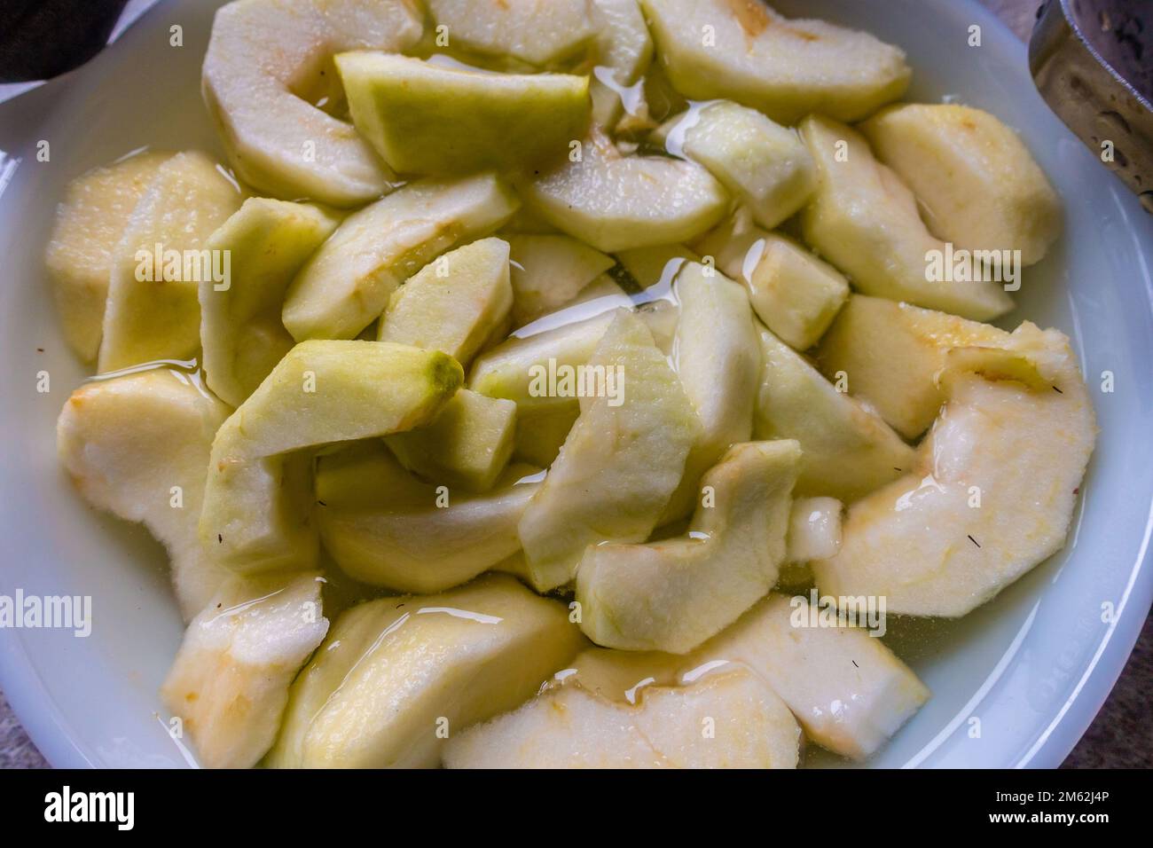 Pommes pelées et tranchées dans un plat d'eau prêt à faire de la sauce ...