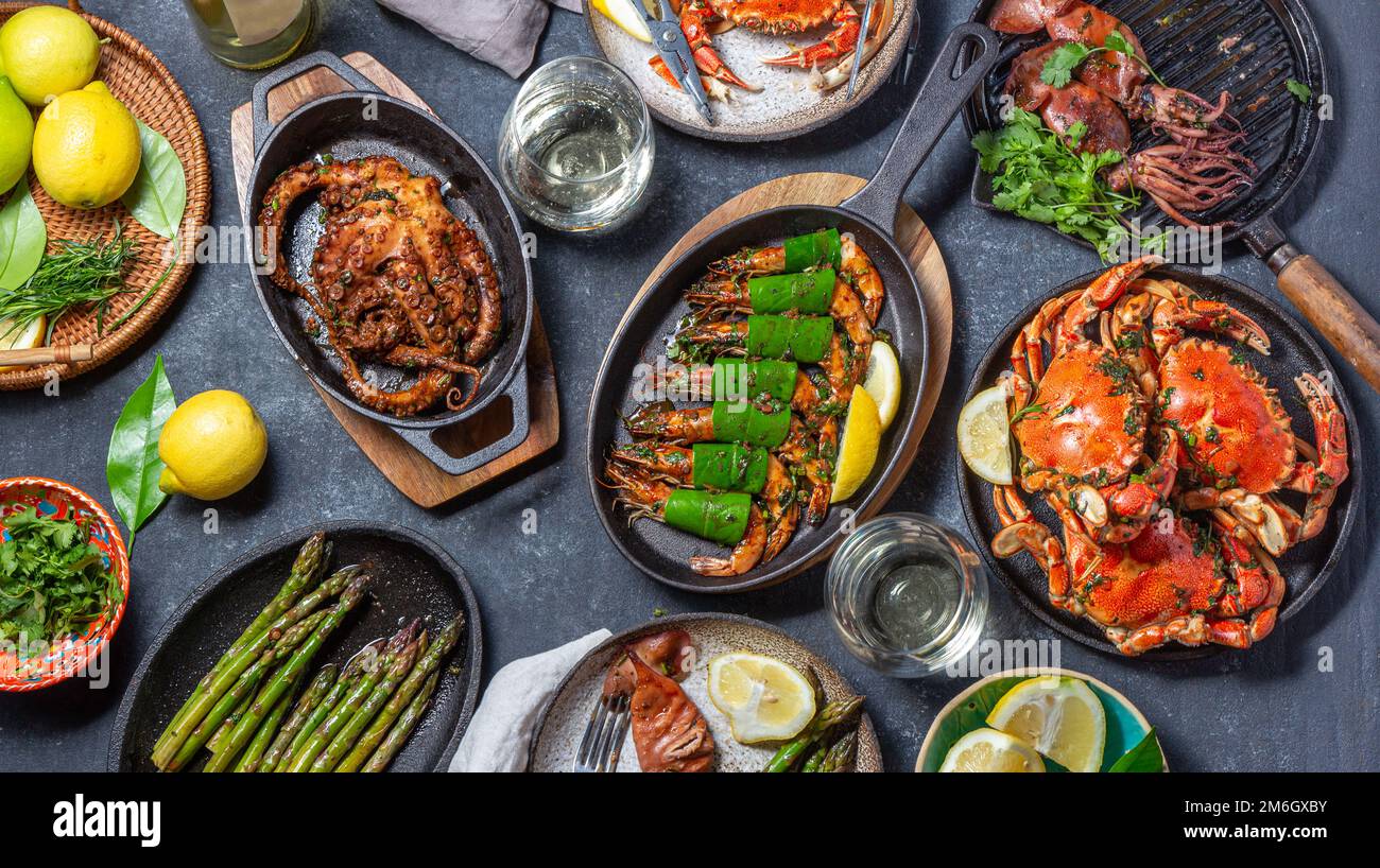 Table avec plats de fruits de mer - crabes cuits, crevettes tigrées ...