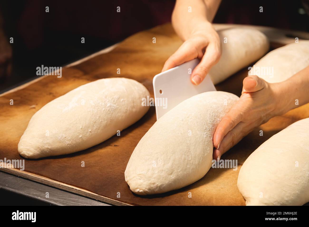 Un pain cru de pain français se trouve sur une planche de bois ...