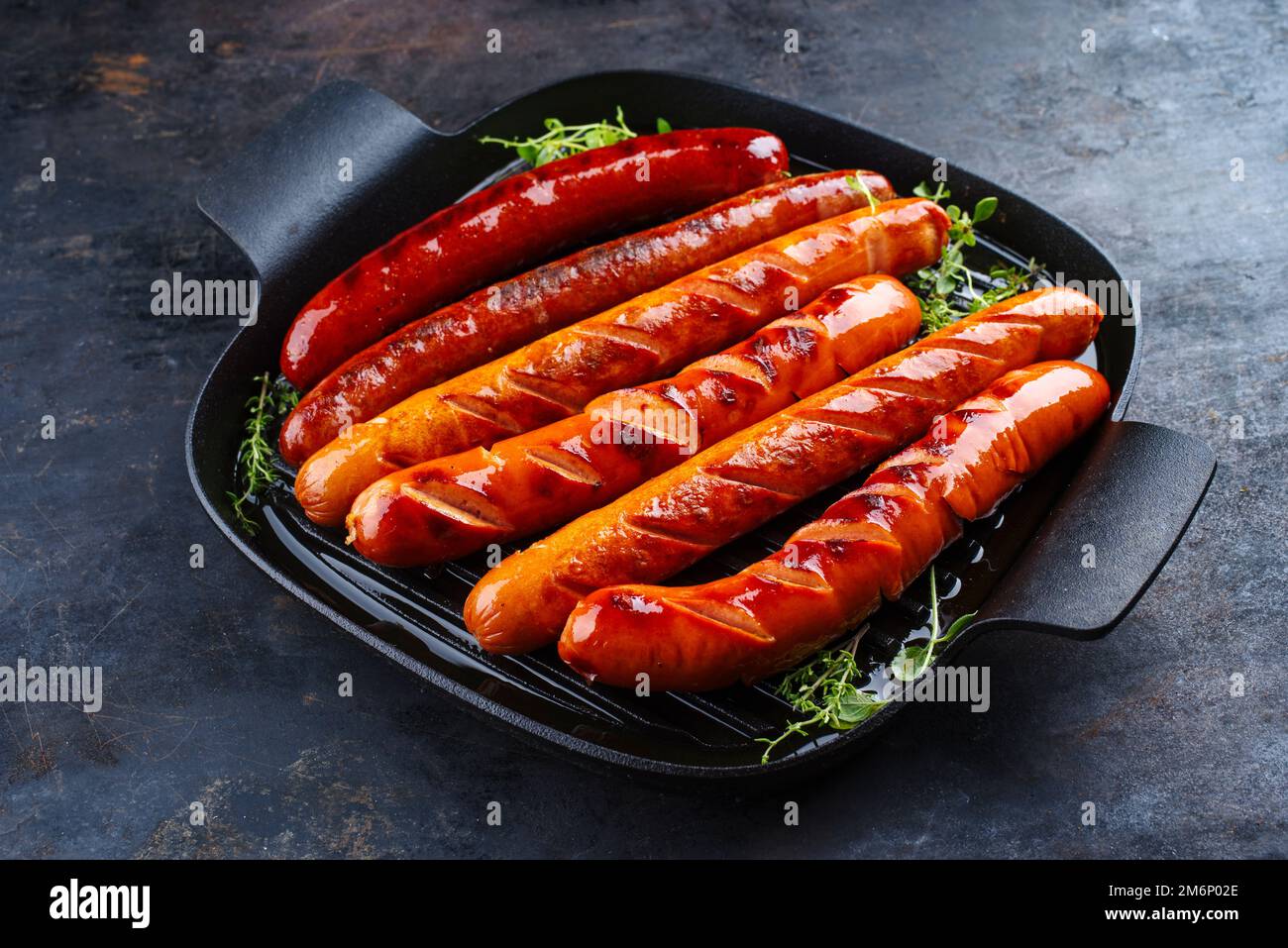 Des saucisses traditionnelles allemandes de Bratwurst sont servies dans une poêle rustique en ...