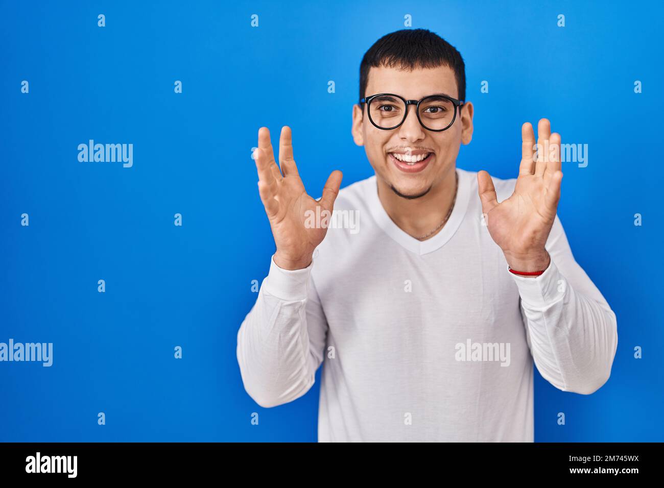 Jeune homme arabe portant une chemise blanche et des lunettes ...