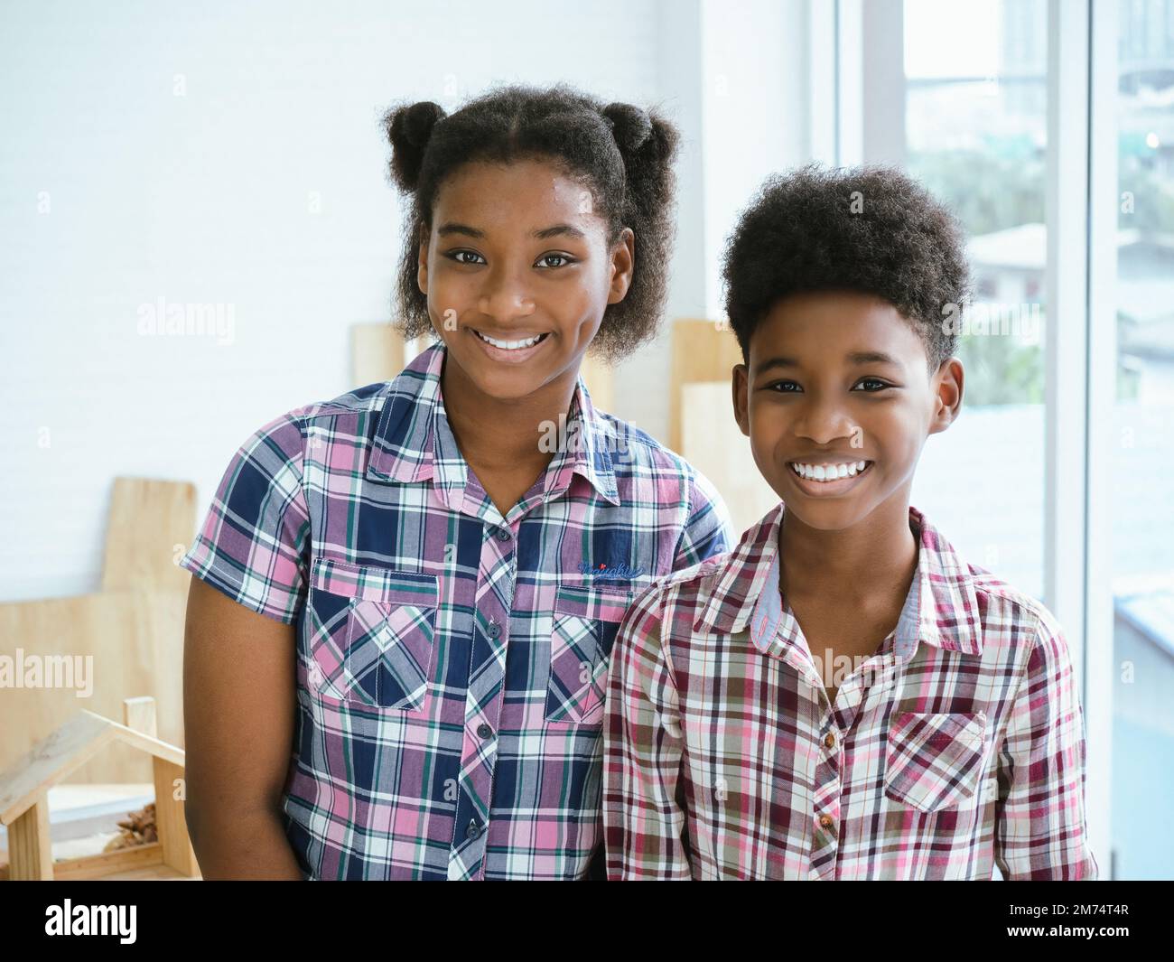 Deux frères et sœurs afro-américains embrassent le cou et regardent le ...