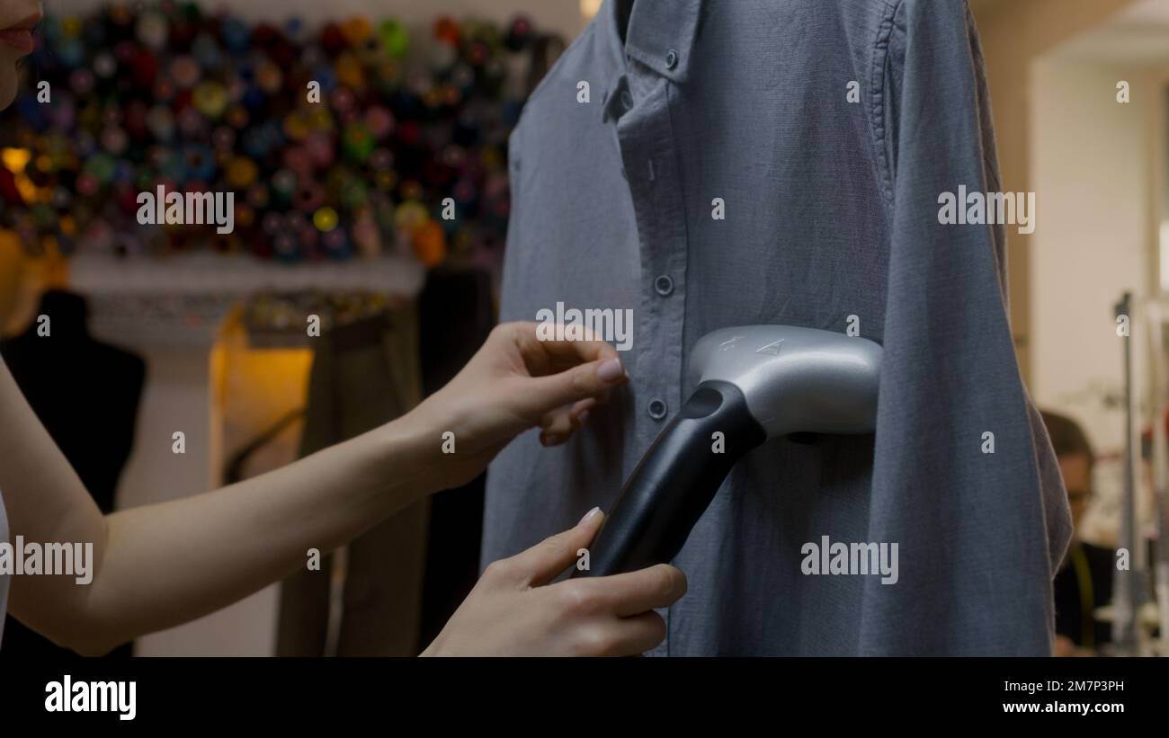 Gros plan d'une femme redonne une chemise ajustée avec défroisseur ...