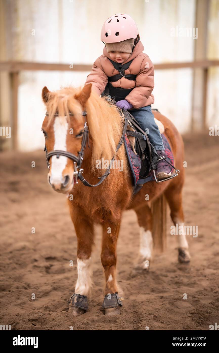 Leçon de équitation pour les petits enfants. Une jeune fille de trois ...