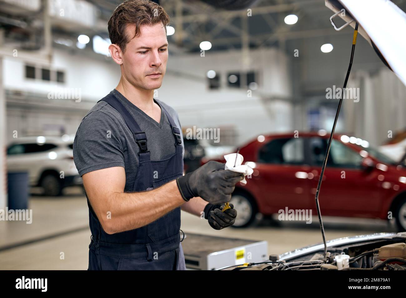 jeune mécanicien caucasien en uniforme faisant l'entretien et l'entretien de voiture ...