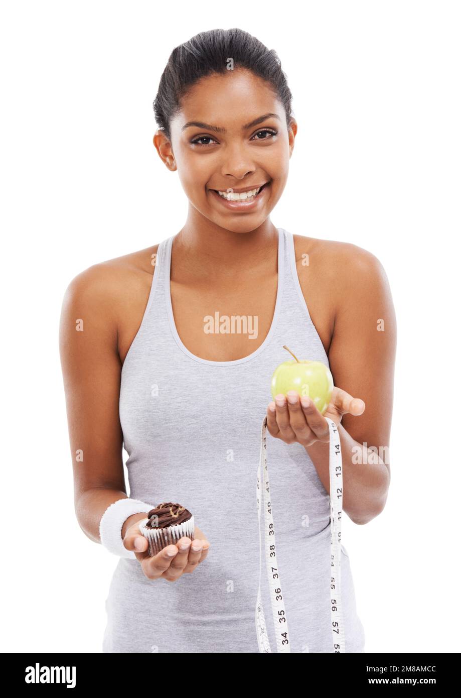 Peser ses décisions de régime. Une jolie jeune femme pesant un cupcake ...