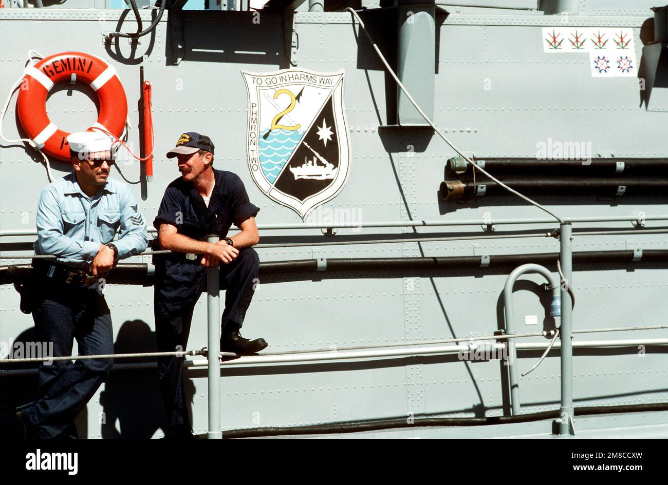 Deux marins se penchent sur une rambarde du côté tribord de l'hydrofoil ...