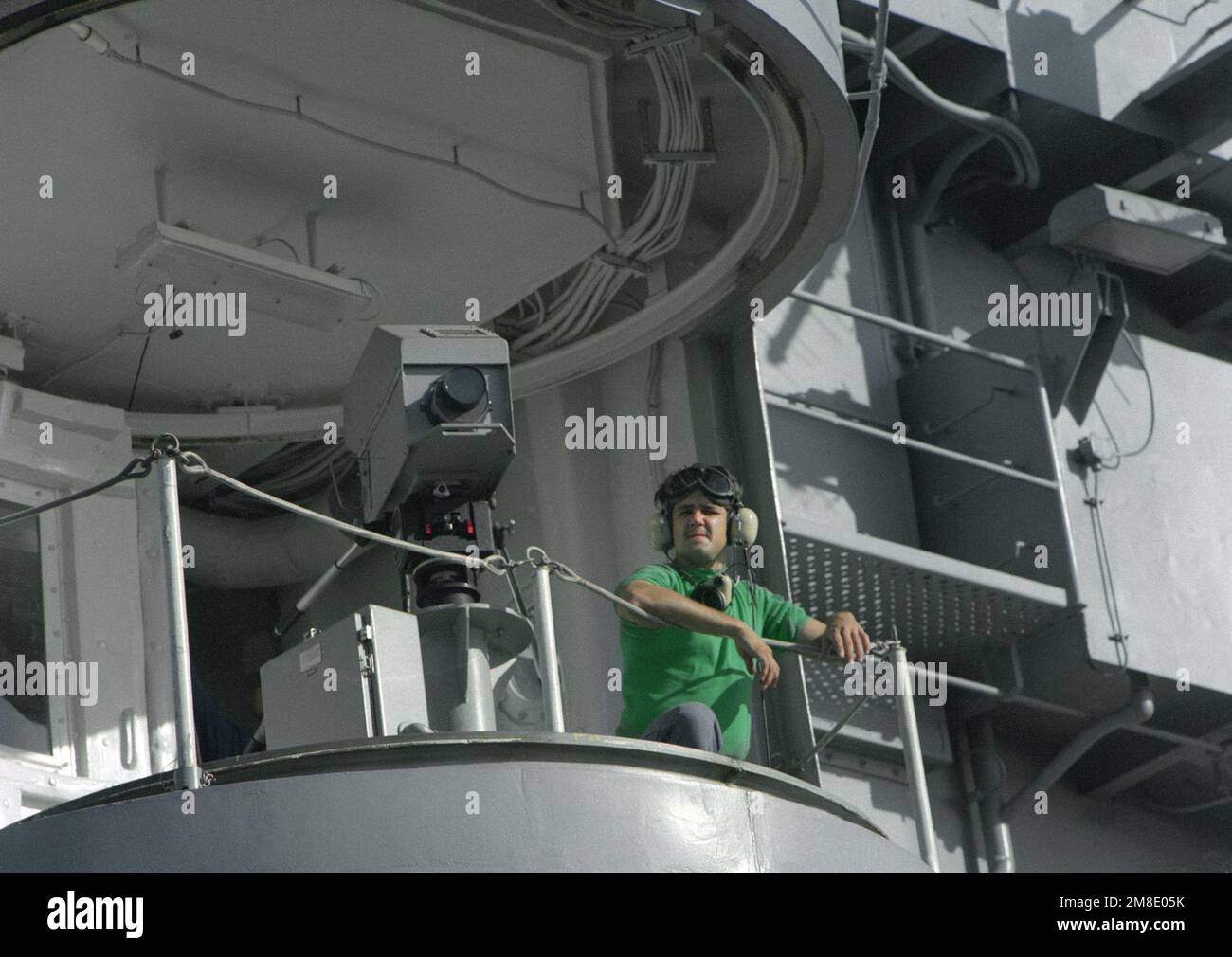 Un membre de l'équipage se tient sur la rambarde à côté d'une caméra ...