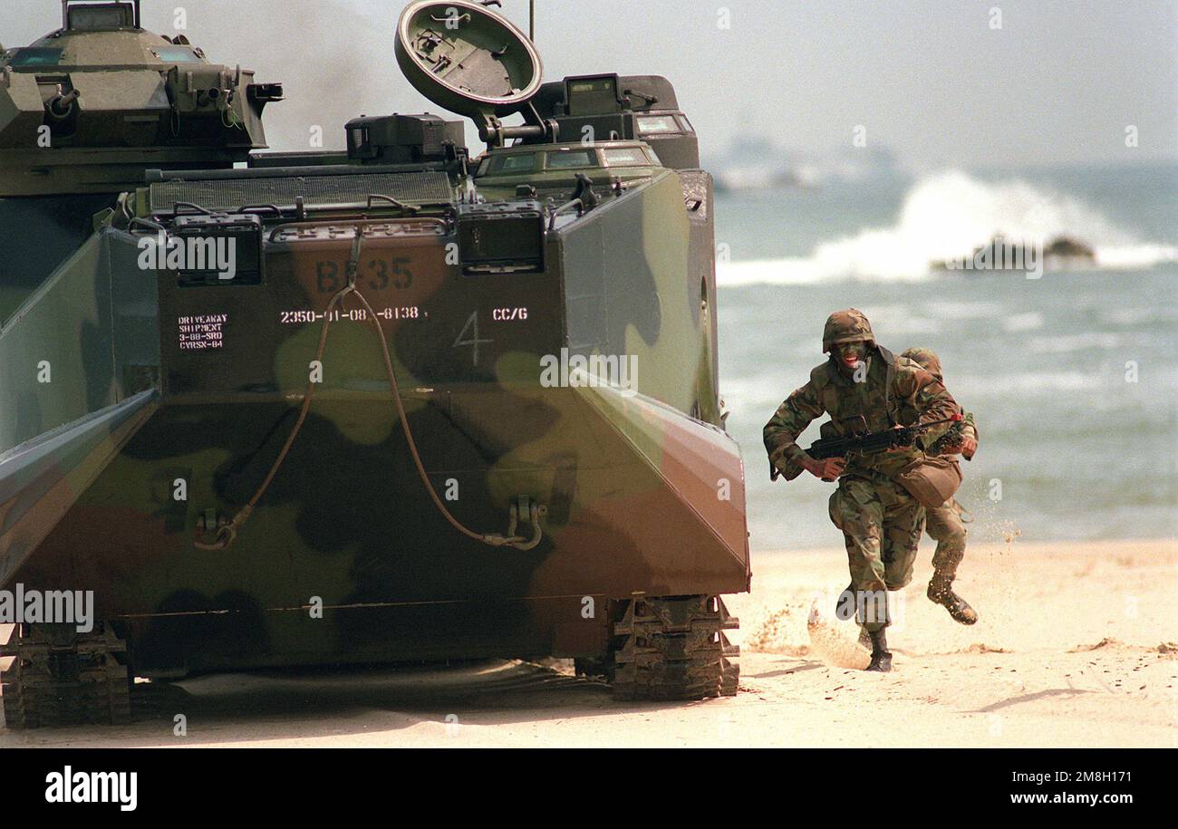 Une Marine armée d'une arme automatique M-249 charge la plage après ...