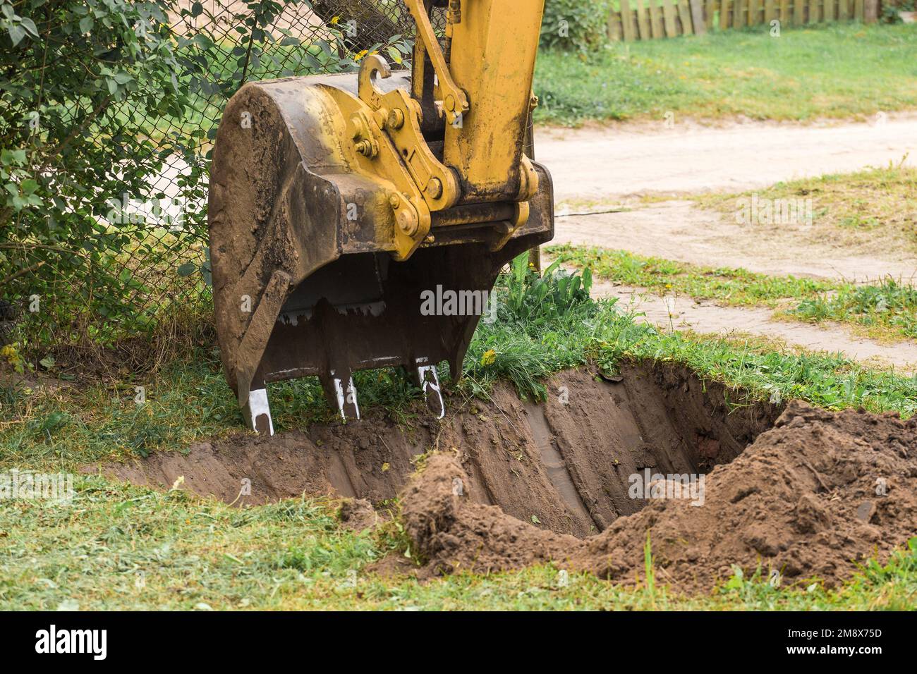 Un godet de bulldozer creuse le sol avec une herbe en gros plan dans ...