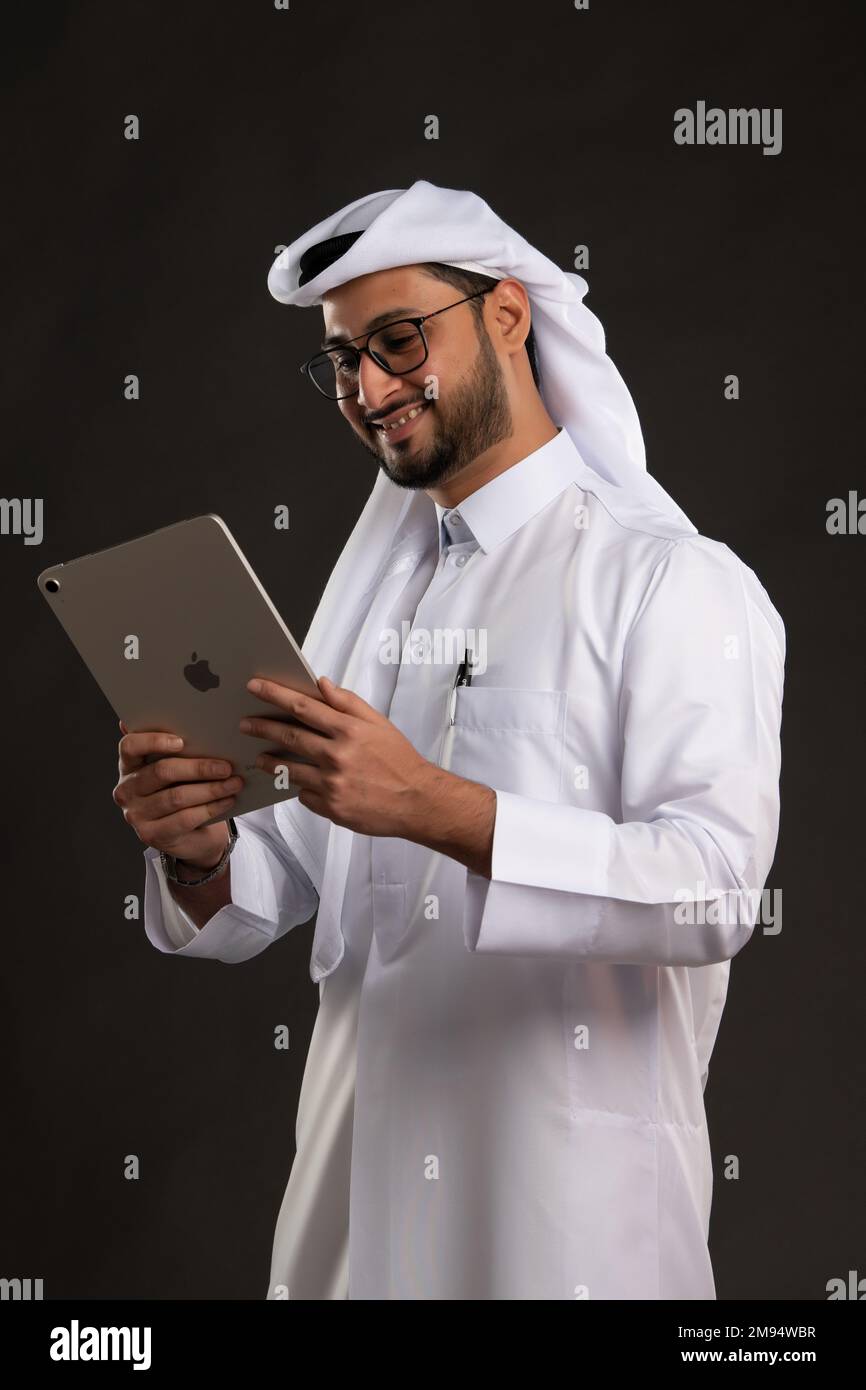 Arabe Qatari homme utilisant le tablate et posant sur un fond isolé ...