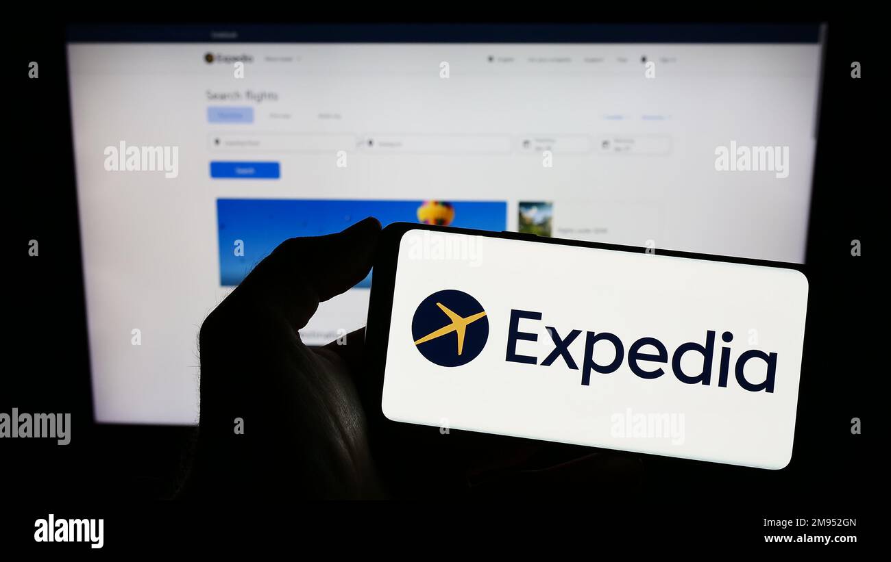 Personne tenant un téléphone portable avec le logo d'affaires de l'agence de voyage en ligne ...