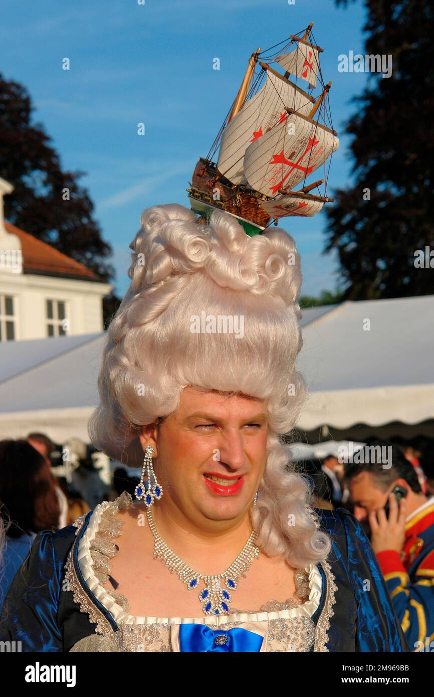 Un homme en drag, dont une perruque blanche avec un bateau modèle au ...